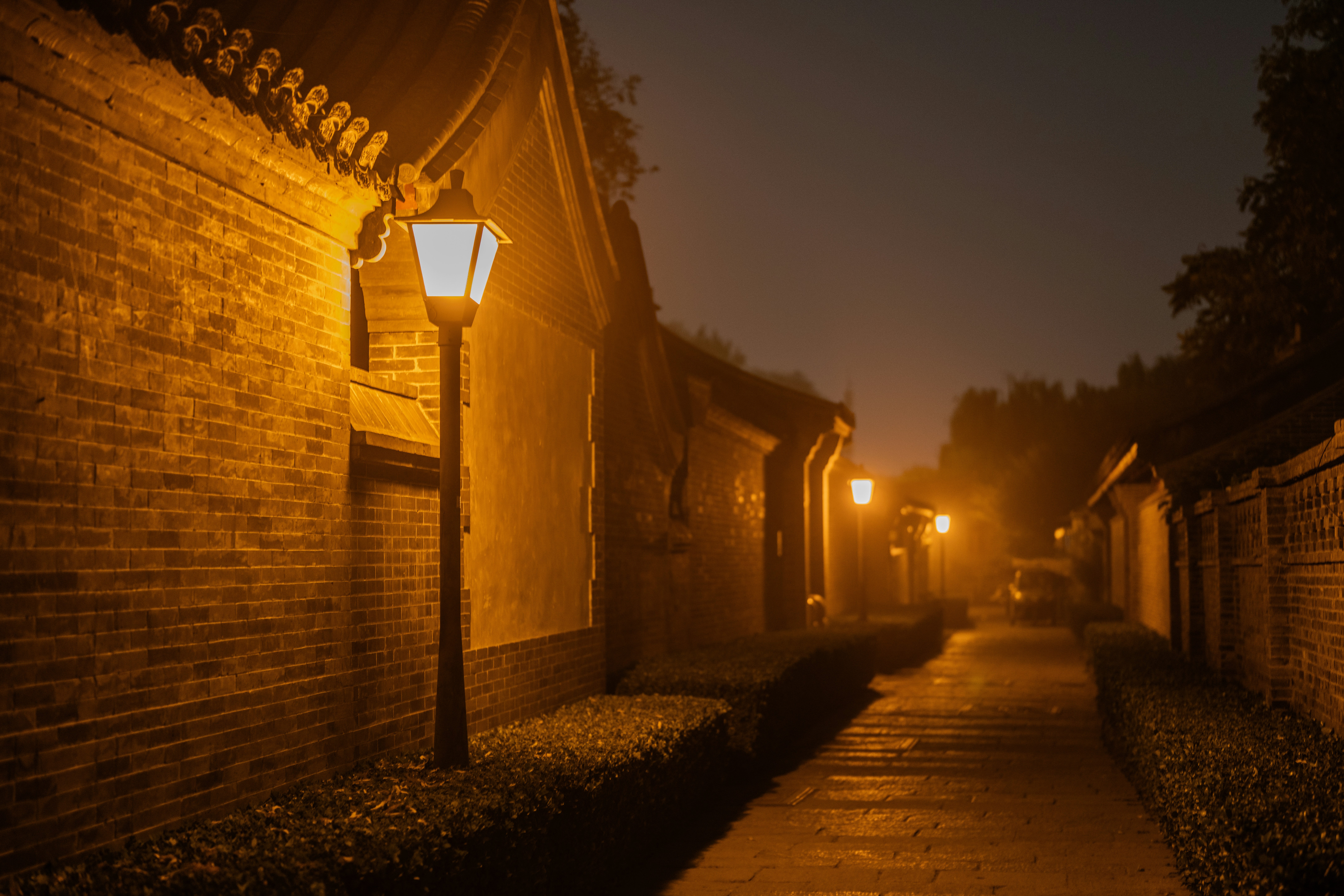 a street light on a brick wall next to a sidewalk