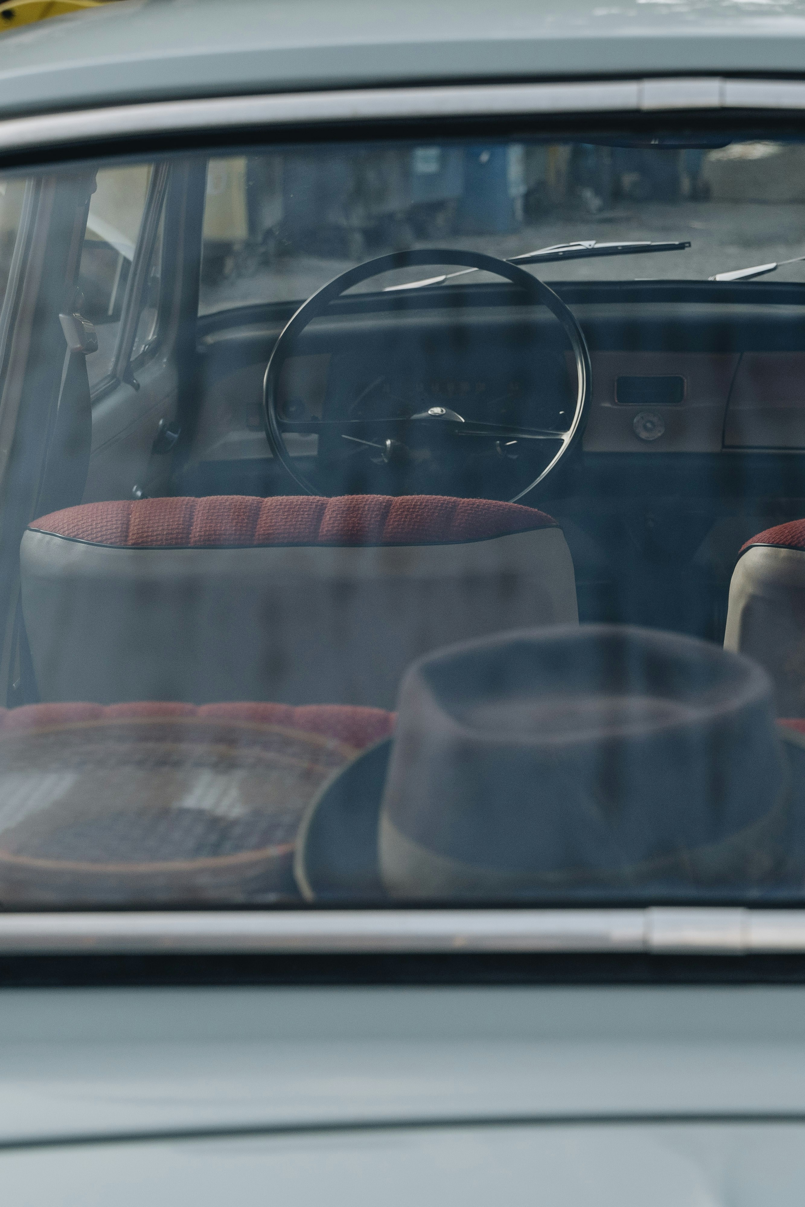 Steering Wheel Echoes: A Fedora Resting in a Vintage Car Interior