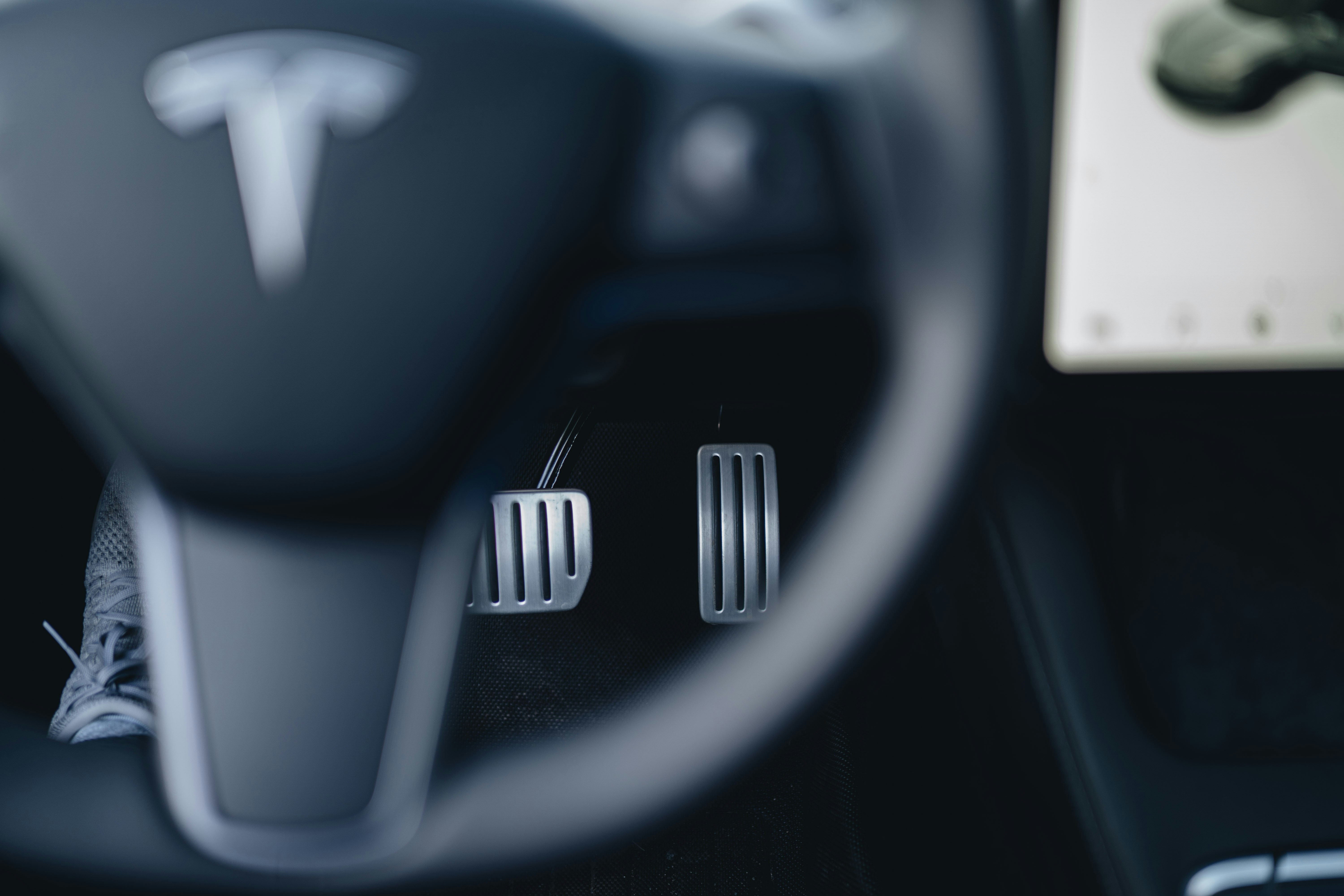 Steering Wheel Foreshadow: Pedals in Focus Beneath a Tesla