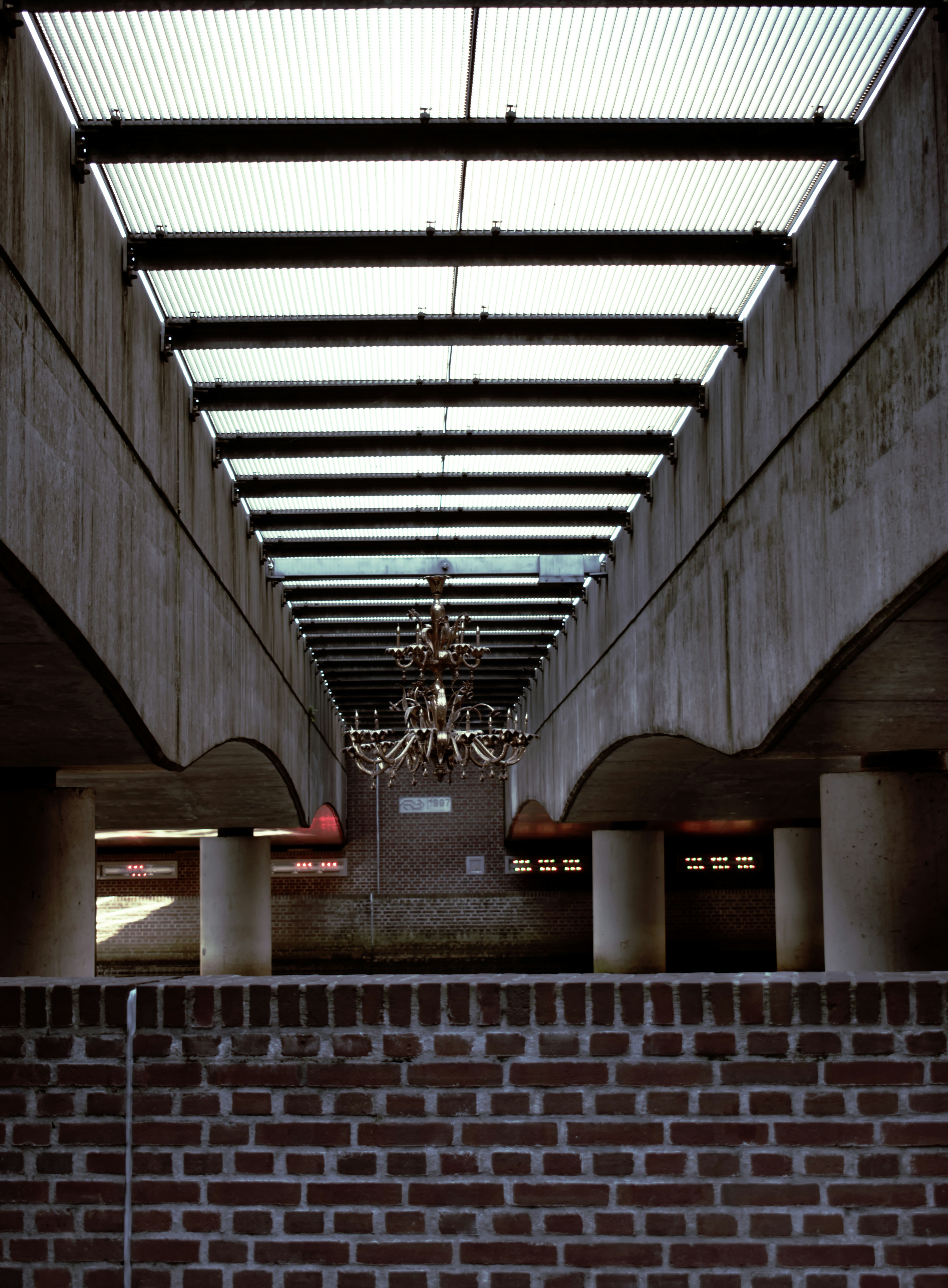Symmetry of Light: A Concrete Atrium's Chandelier Amid Arches