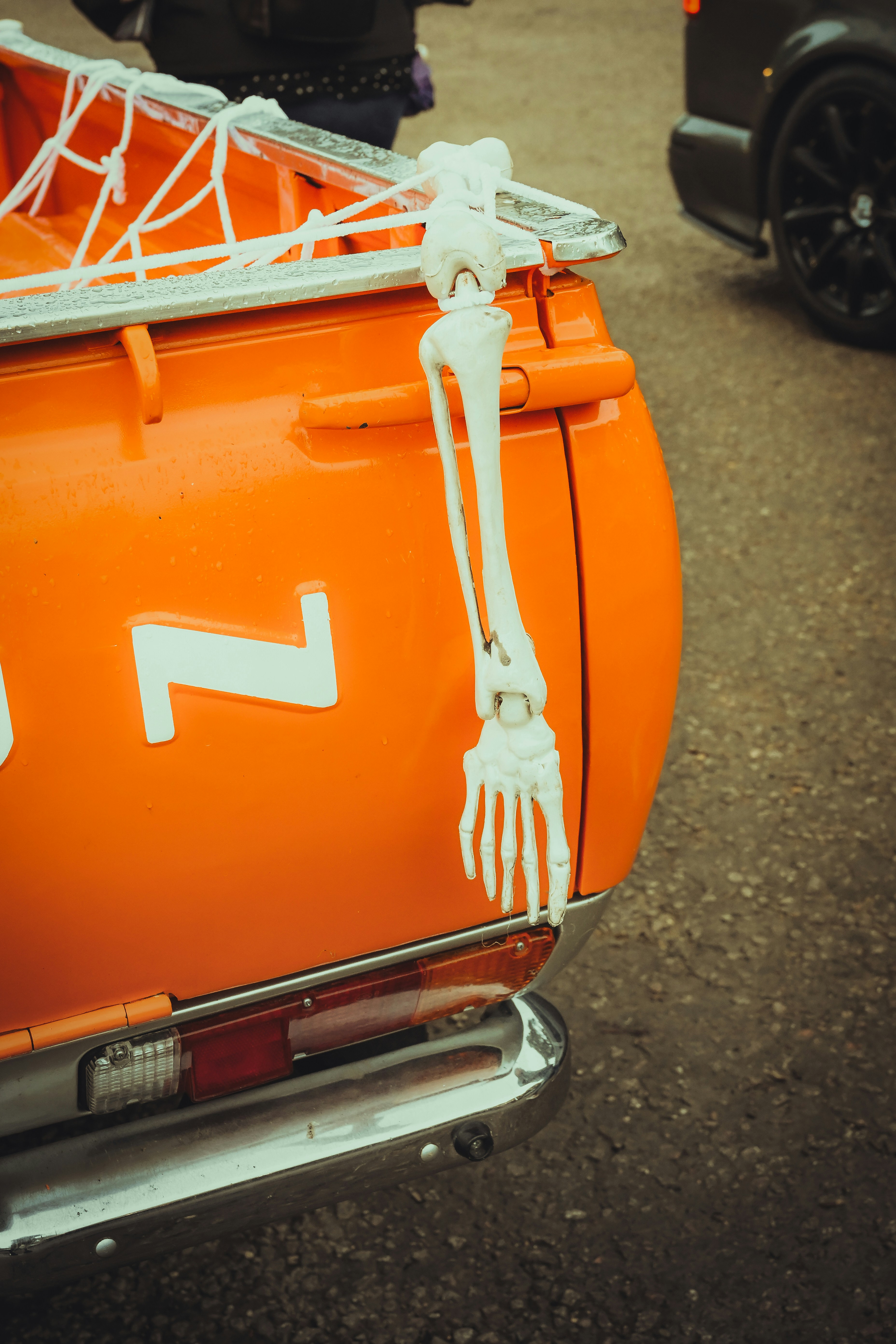 A skeleton sitting on the back of an orange vehicle photo – Free Spooky ...