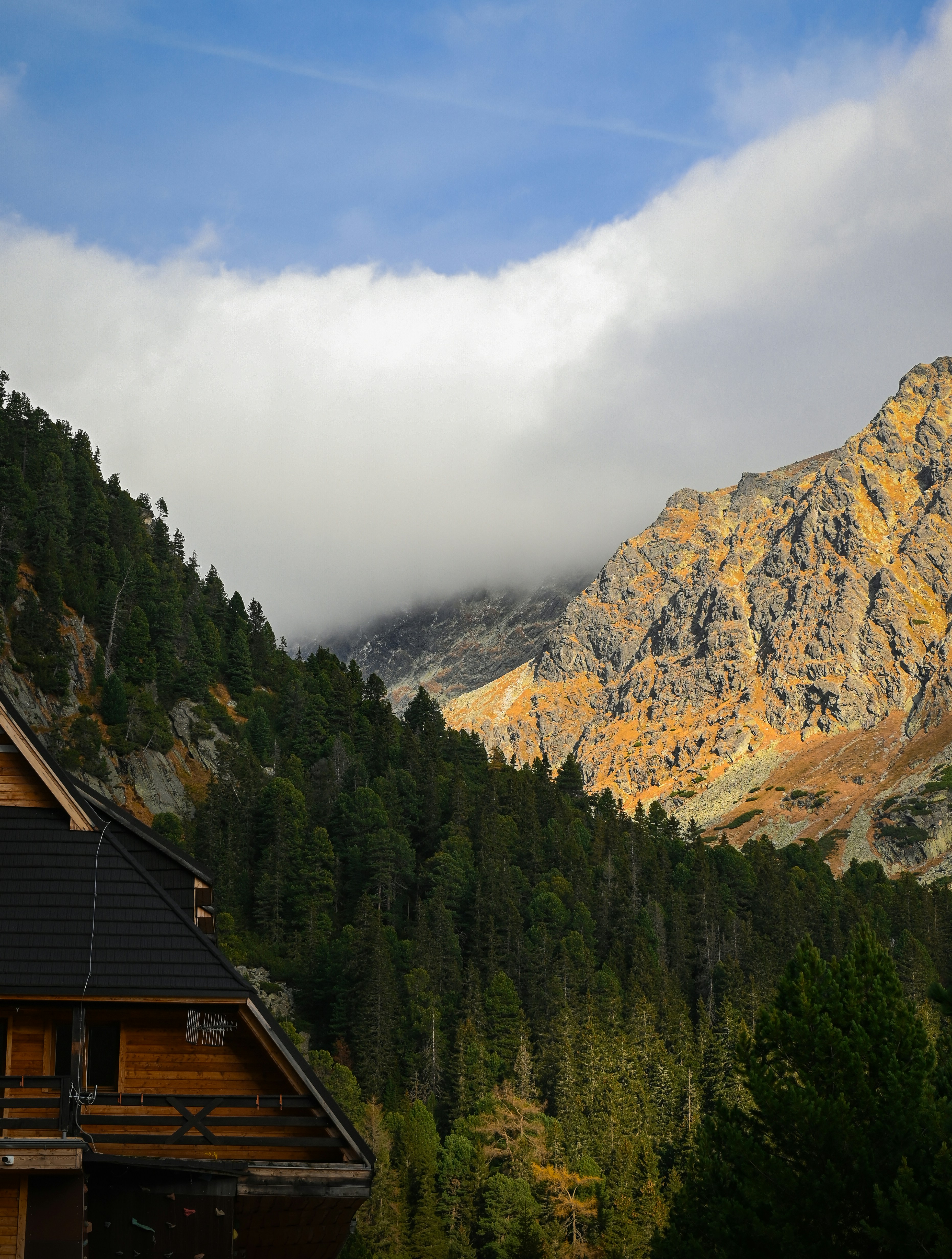 Sunlit Granite Spur Over a Pine-Lined Alpine Valley with a Chalet