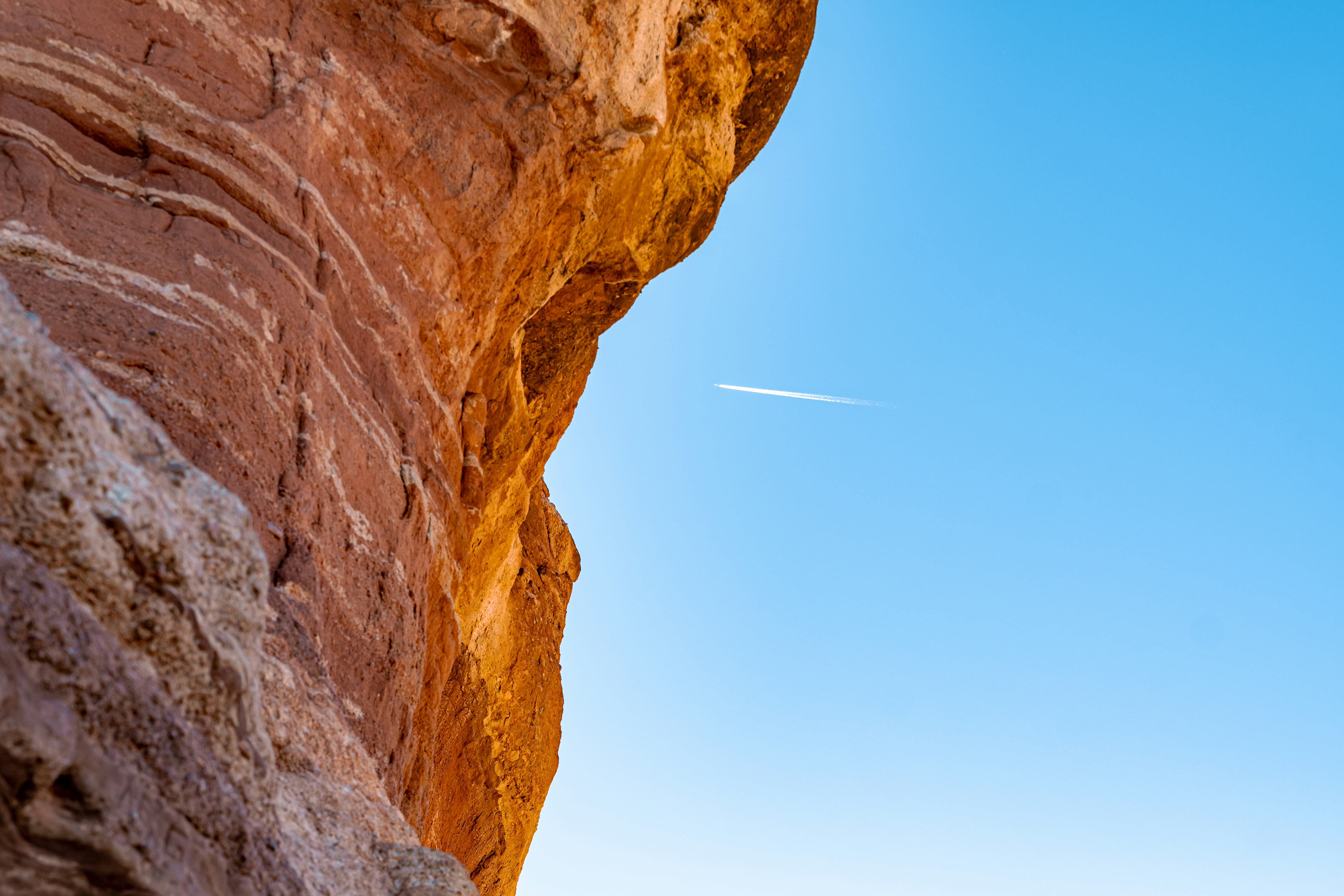 A plane flying in the sky over a rocky cliff photo – Free Mountains ...