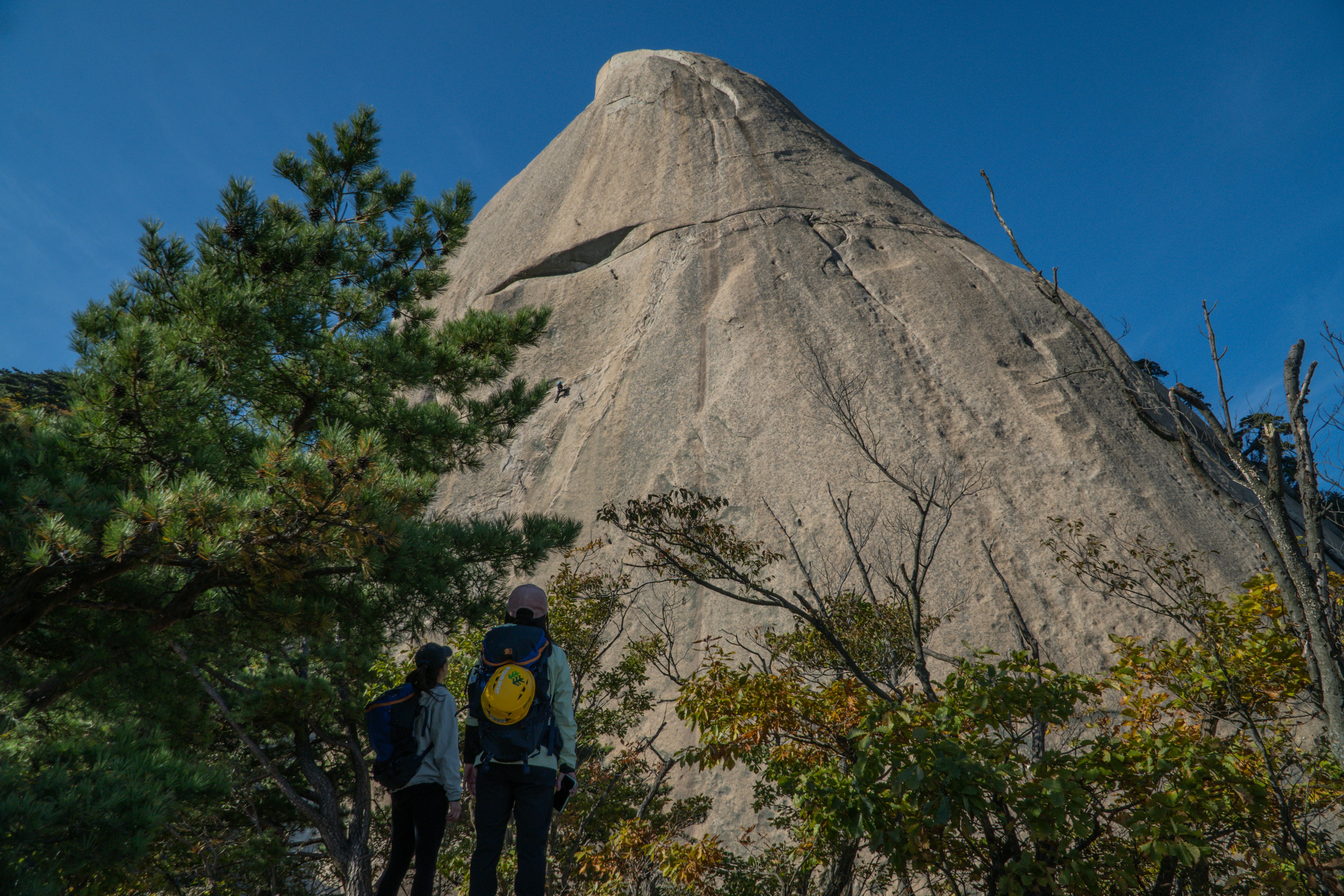 Granite Sentinel: Hikers at the Foot of a Towering Dome