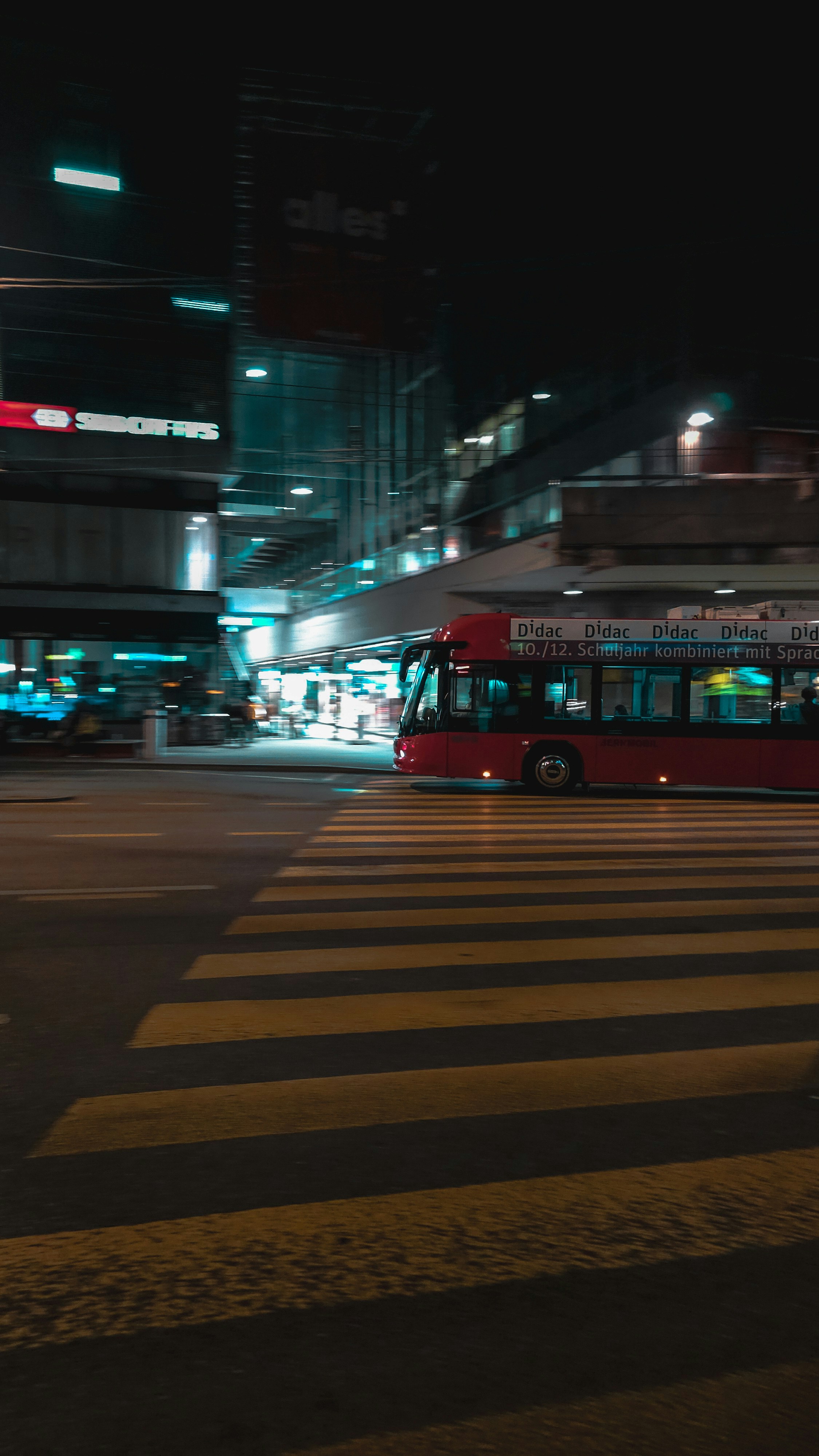 A red bus driving down a street at night photo – Free City Image on ...