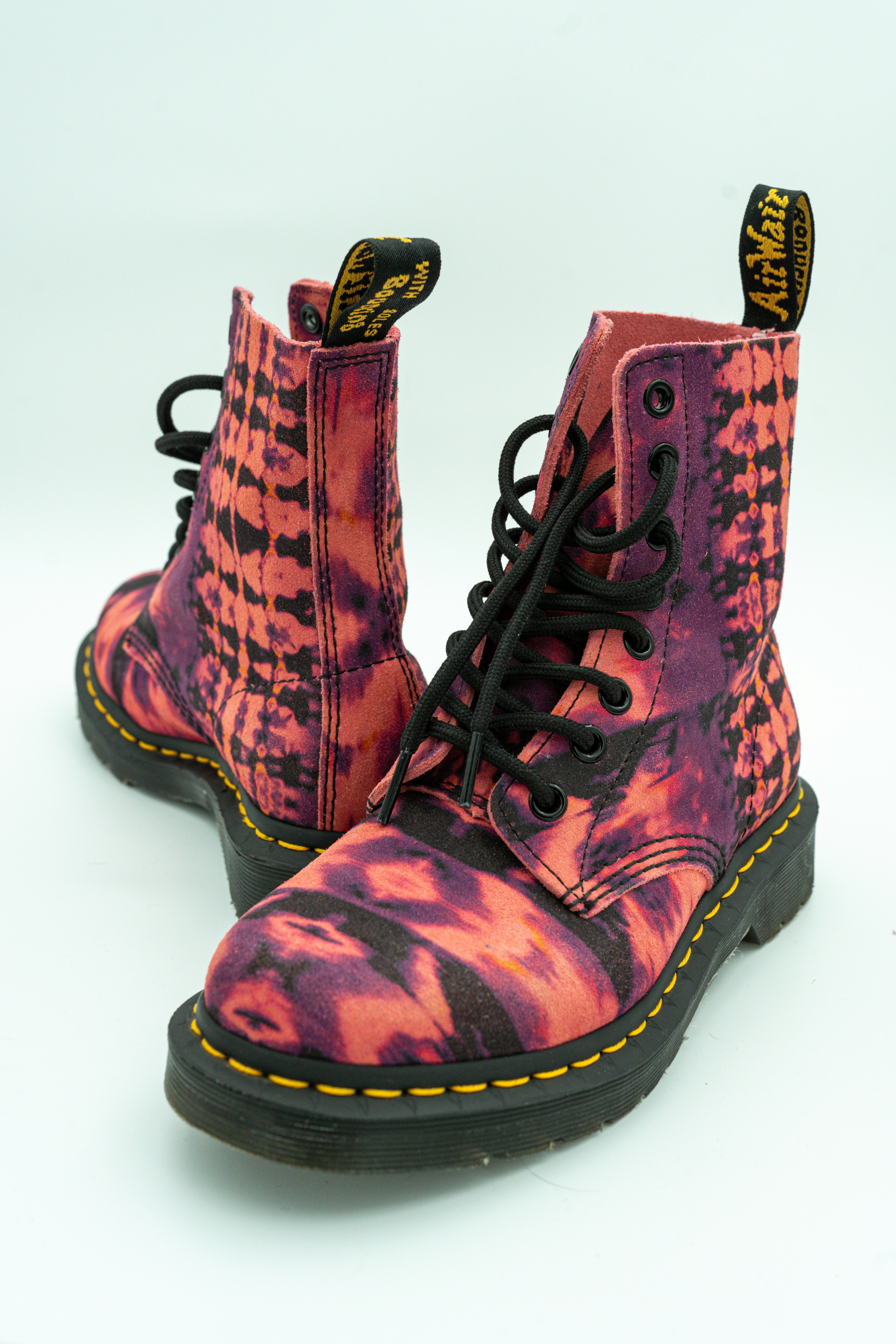 Neon Pink Tie-Dye Combat Boots with Bold Yellow Stitching Under Studio Light