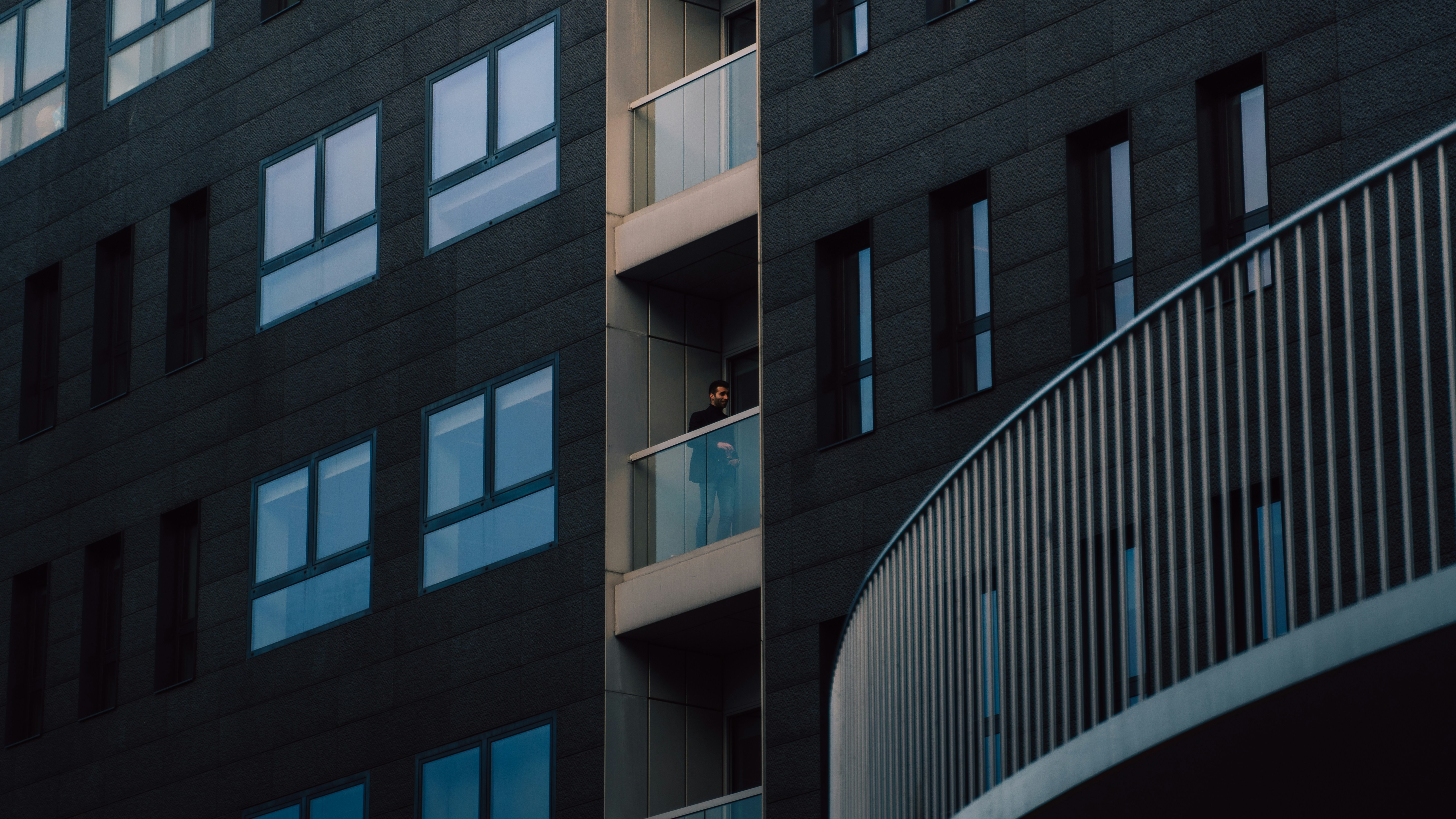 A person standing on a balcony of a building photo – Free Grey Image on ...
