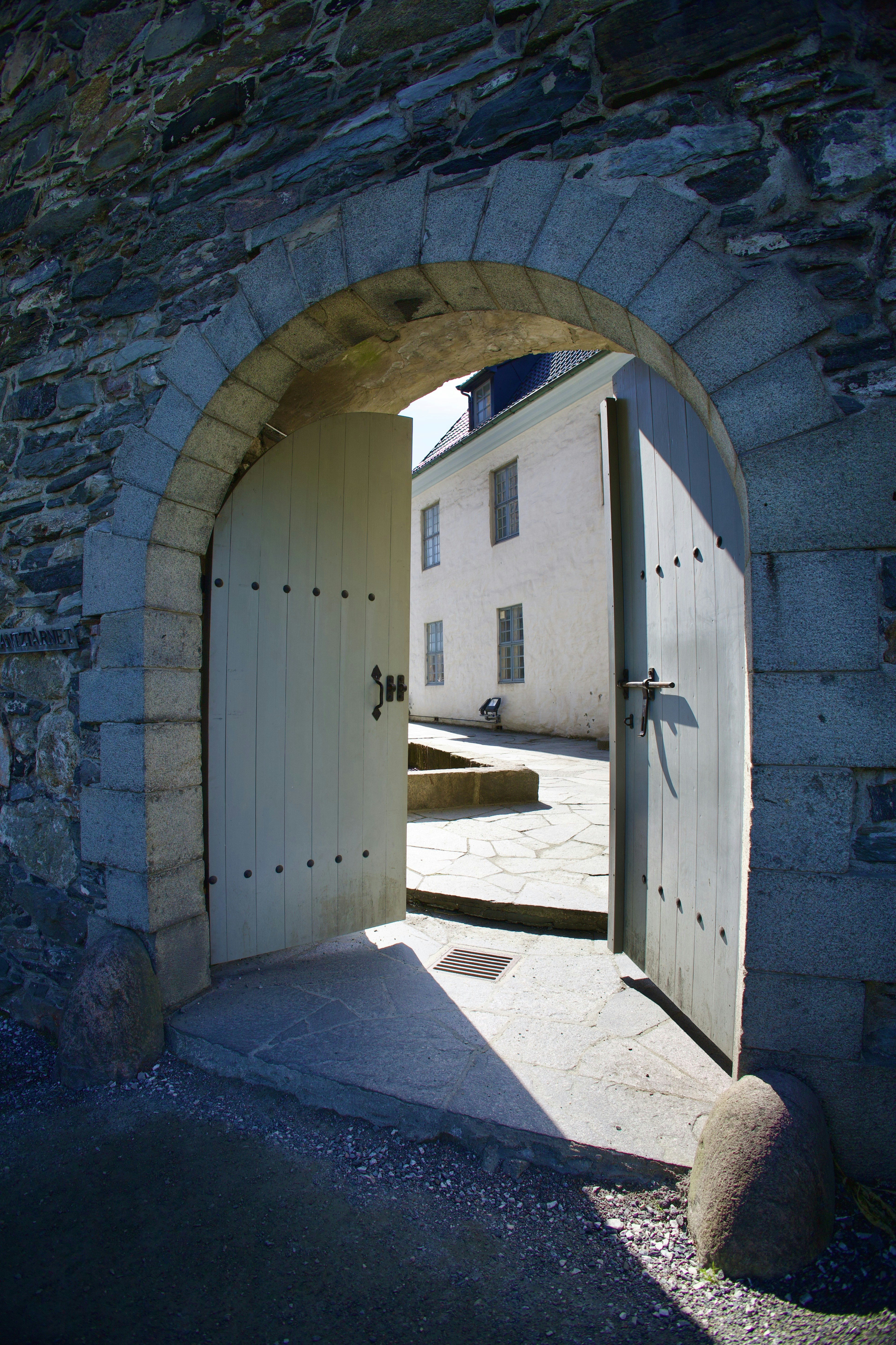 Stone Archway Opens to Sunlit Courtyard and Open doors