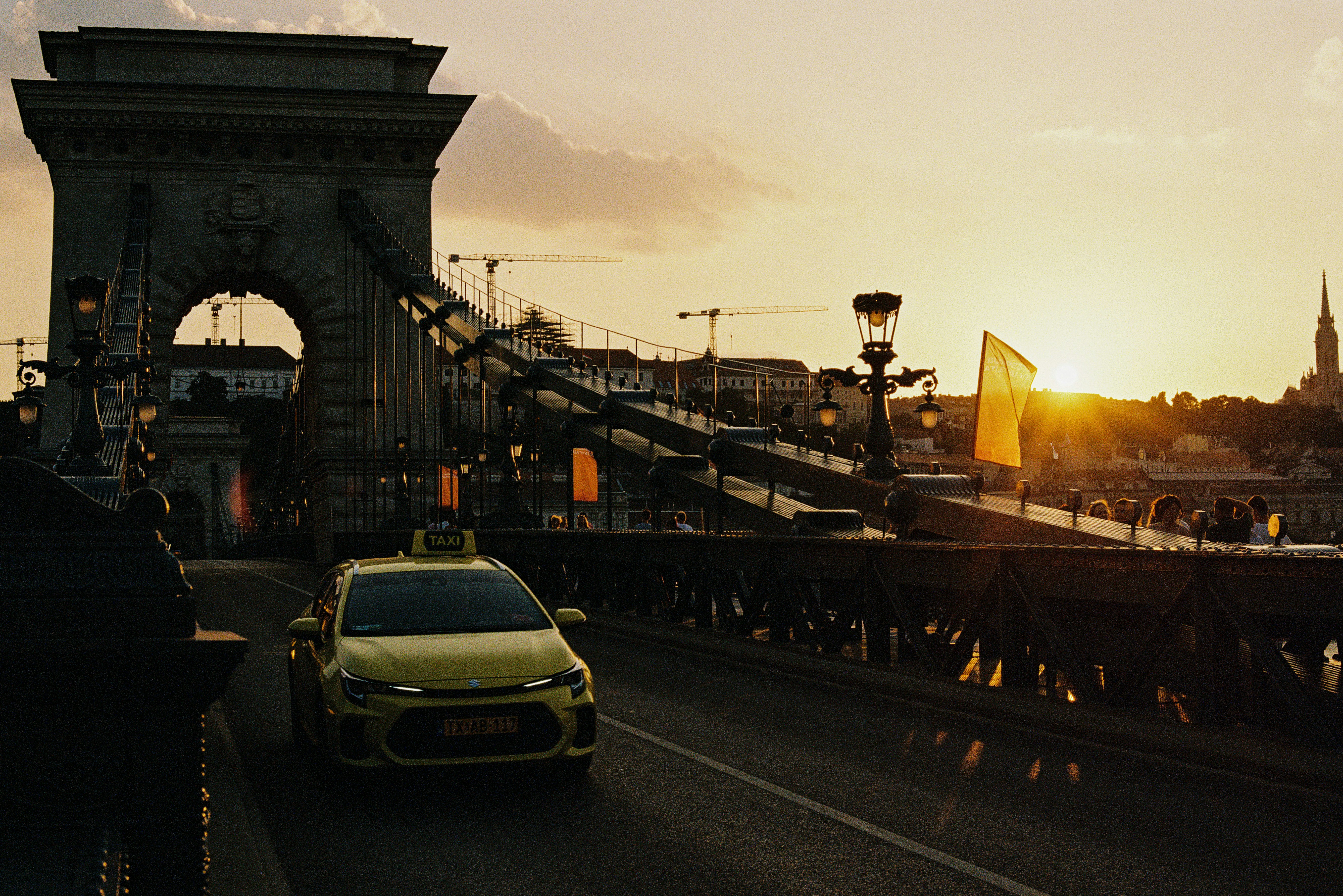 A yellow car driving across a bridge at sunset photo – Free Bridge ...