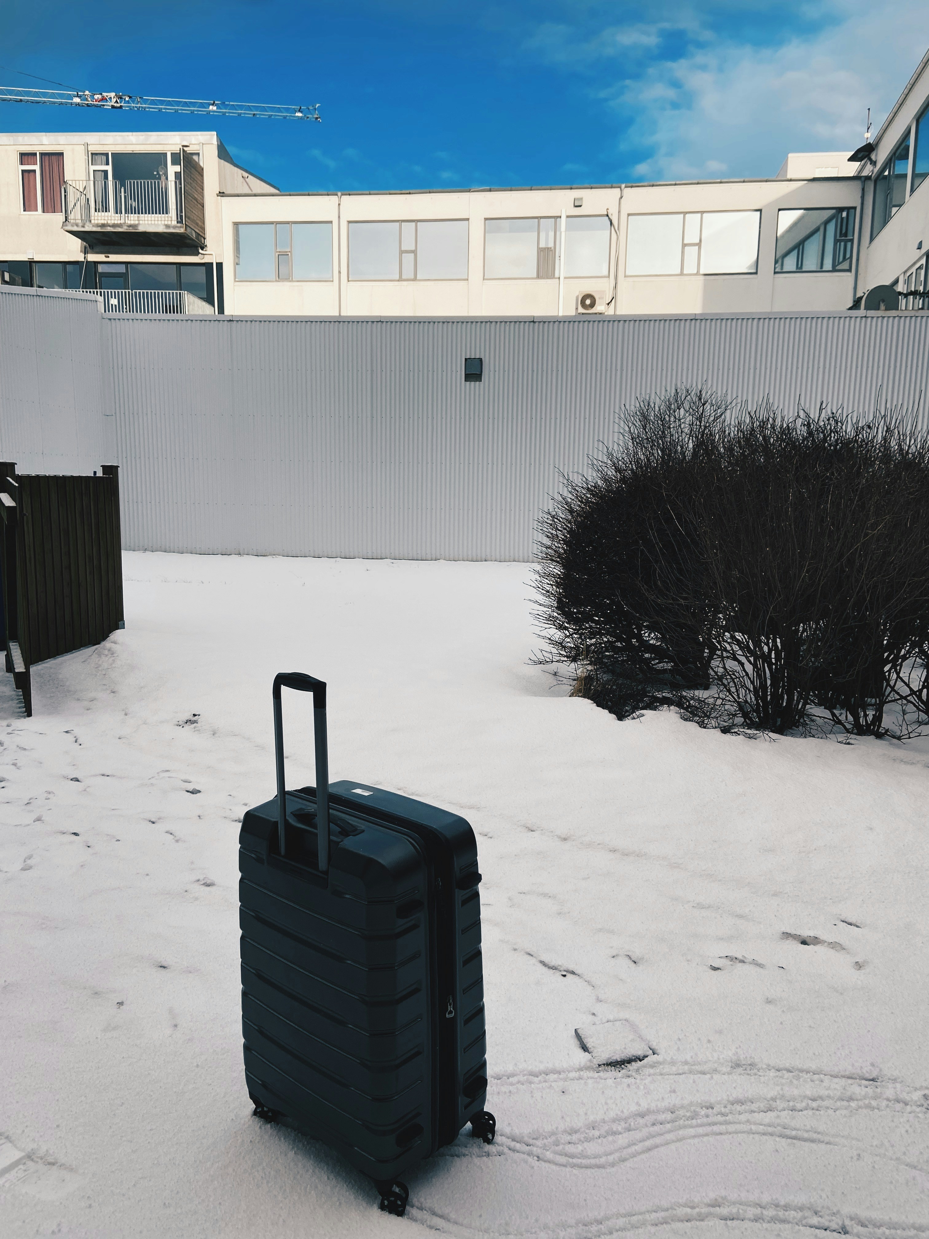 A suitcase sitting in the snow in front of a building photo – Free ...