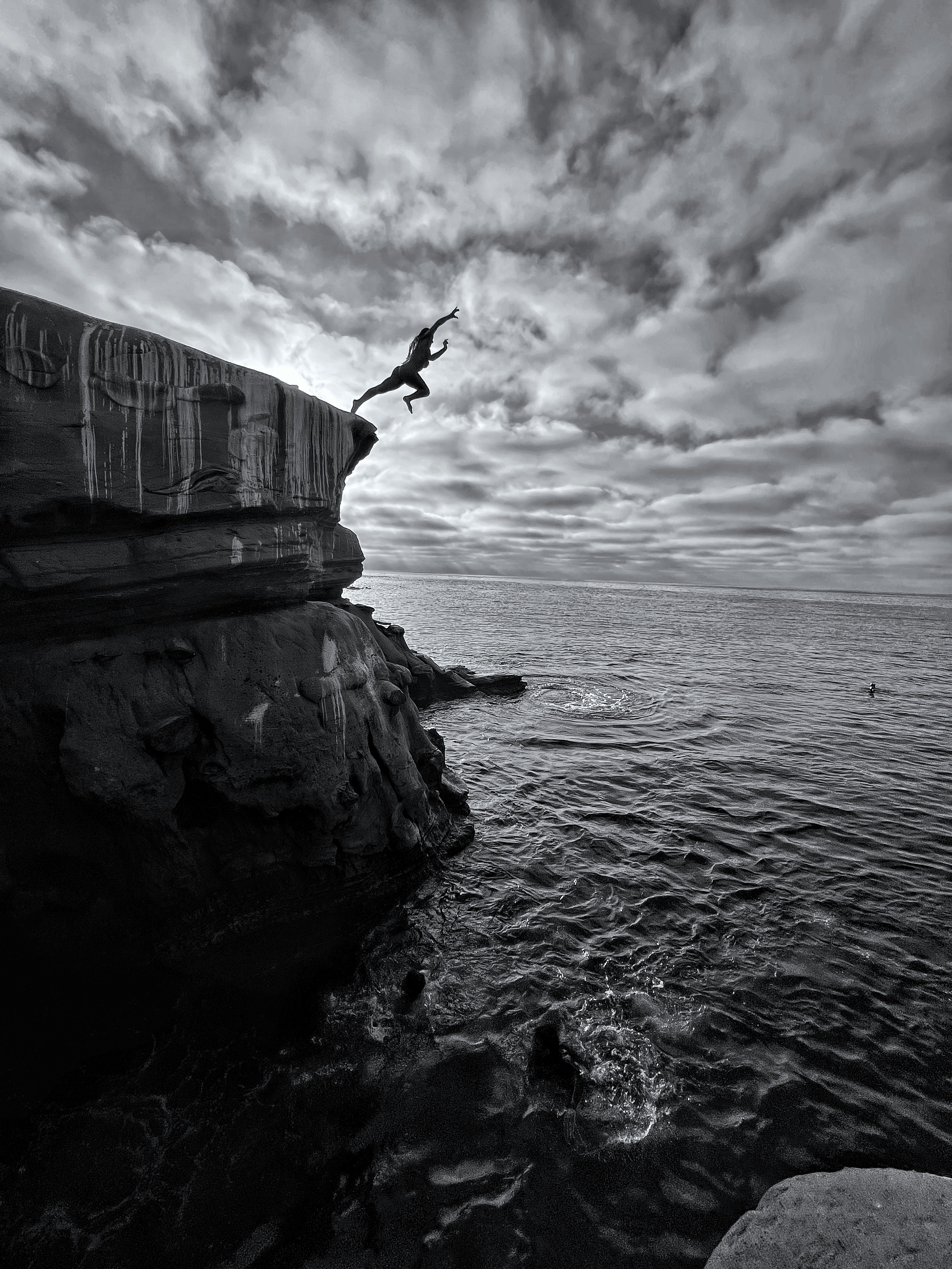 Edge Leap: Silhouette Soars from Cliff into the Sea
