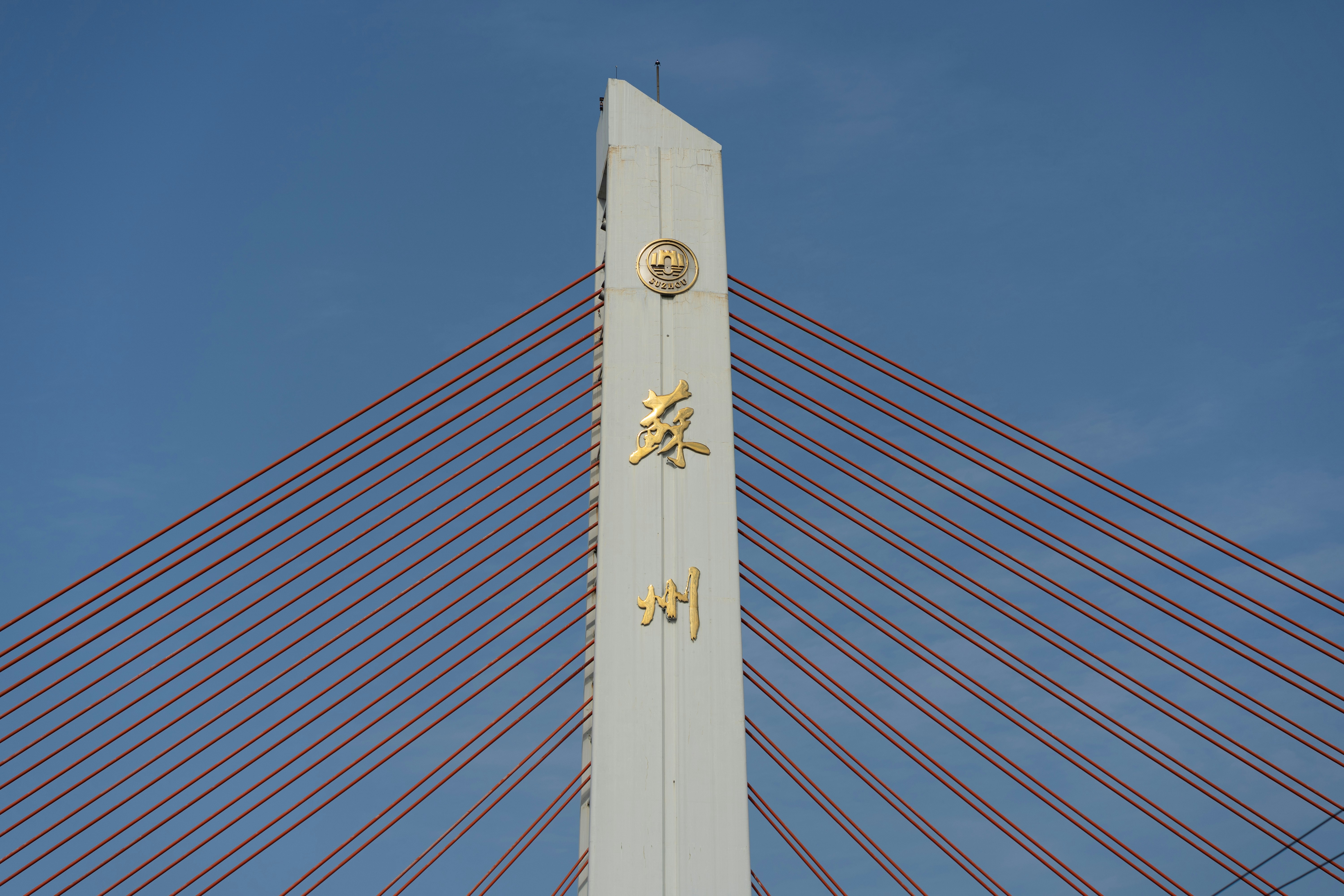 Crimson Cable Web Framing a White Monument Against a Clear Blue Sky
