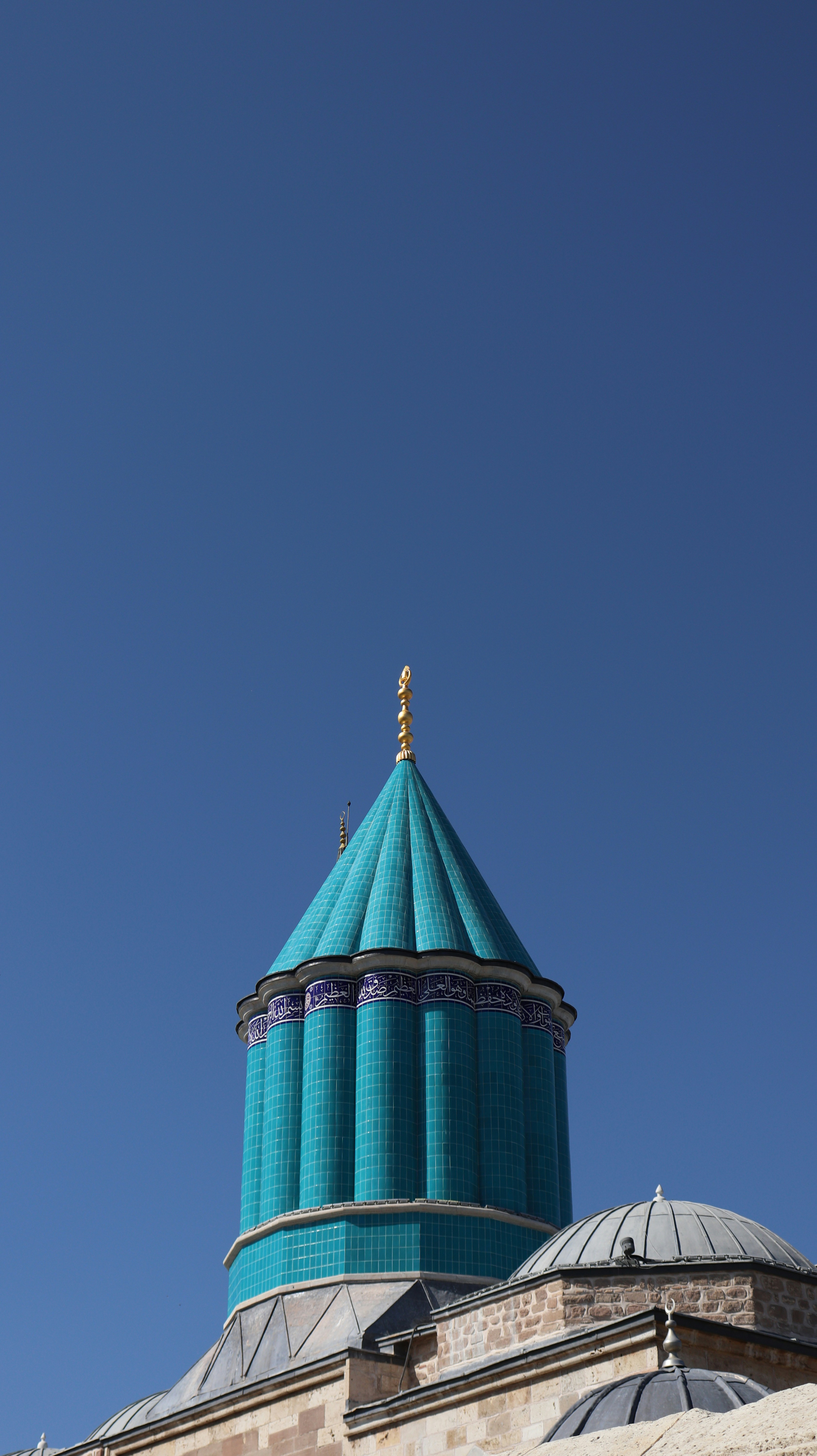 Turquoise Spire Crowned by a Gold Finial Against a Pristine Blue Sky