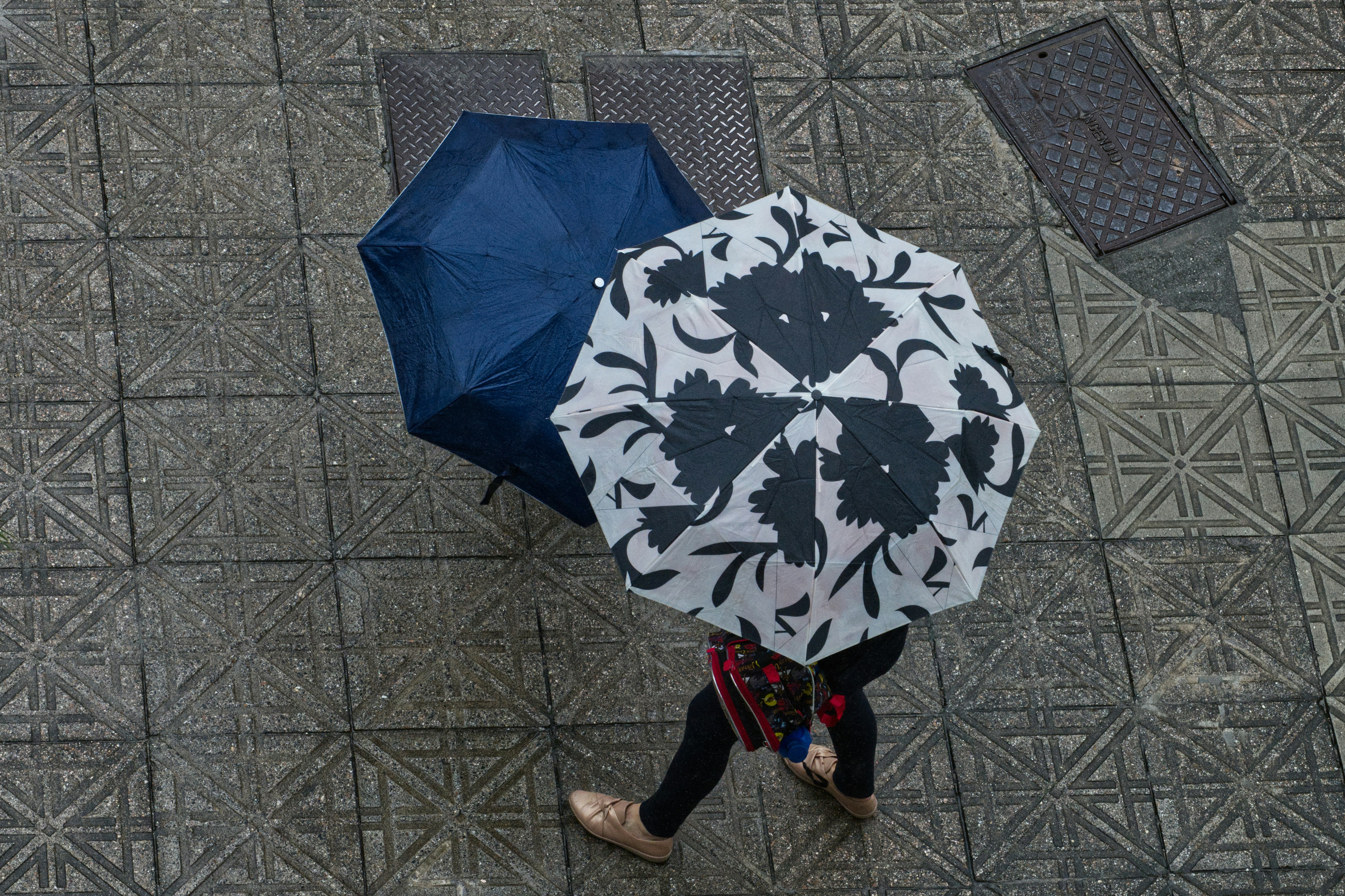 Overhead Duet of Umbrellas Over a Rain-Washed Tile Grid