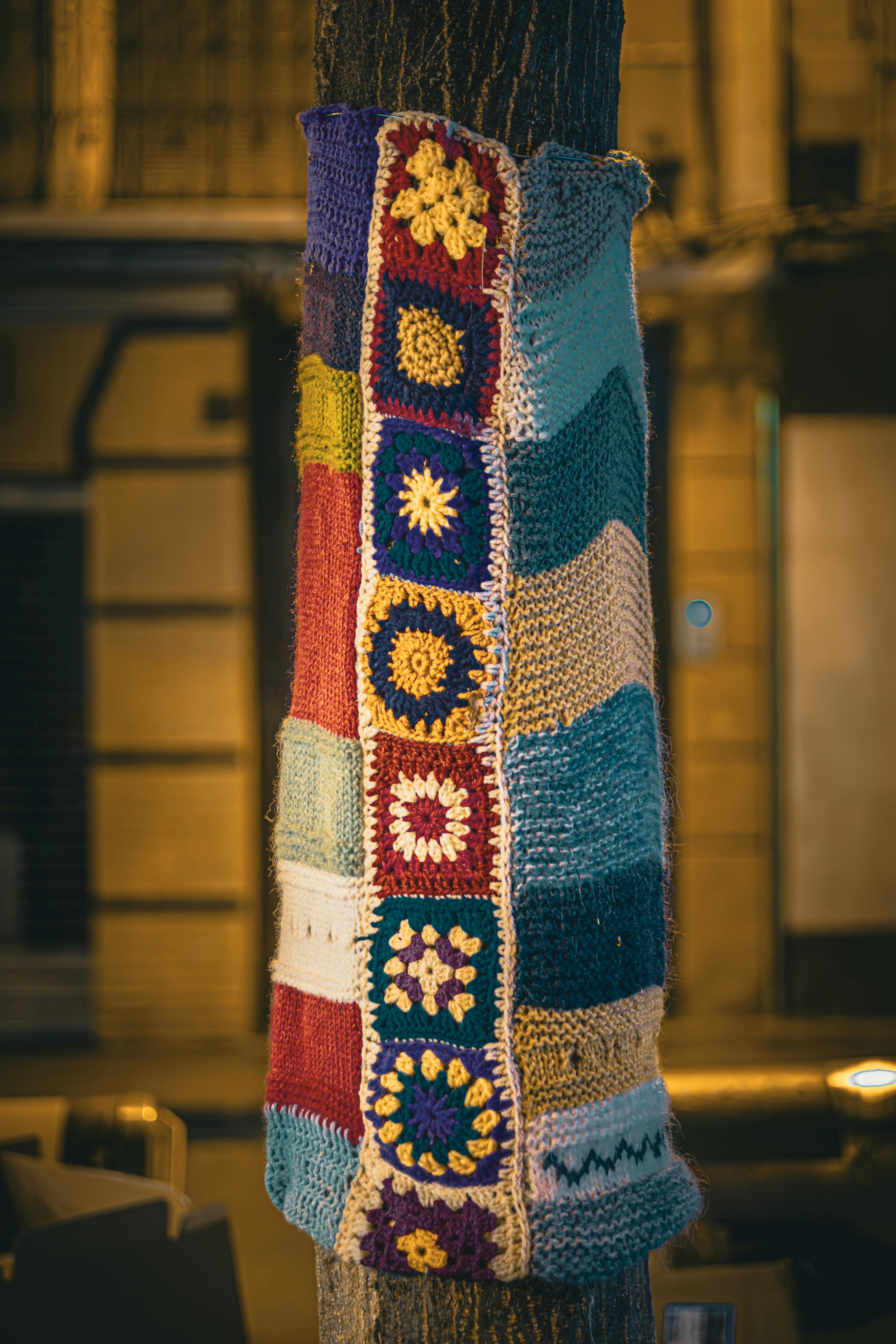 Patchwork on a City Trunk: Night Knit Wrapped Tree Illuminated by Streetlight
