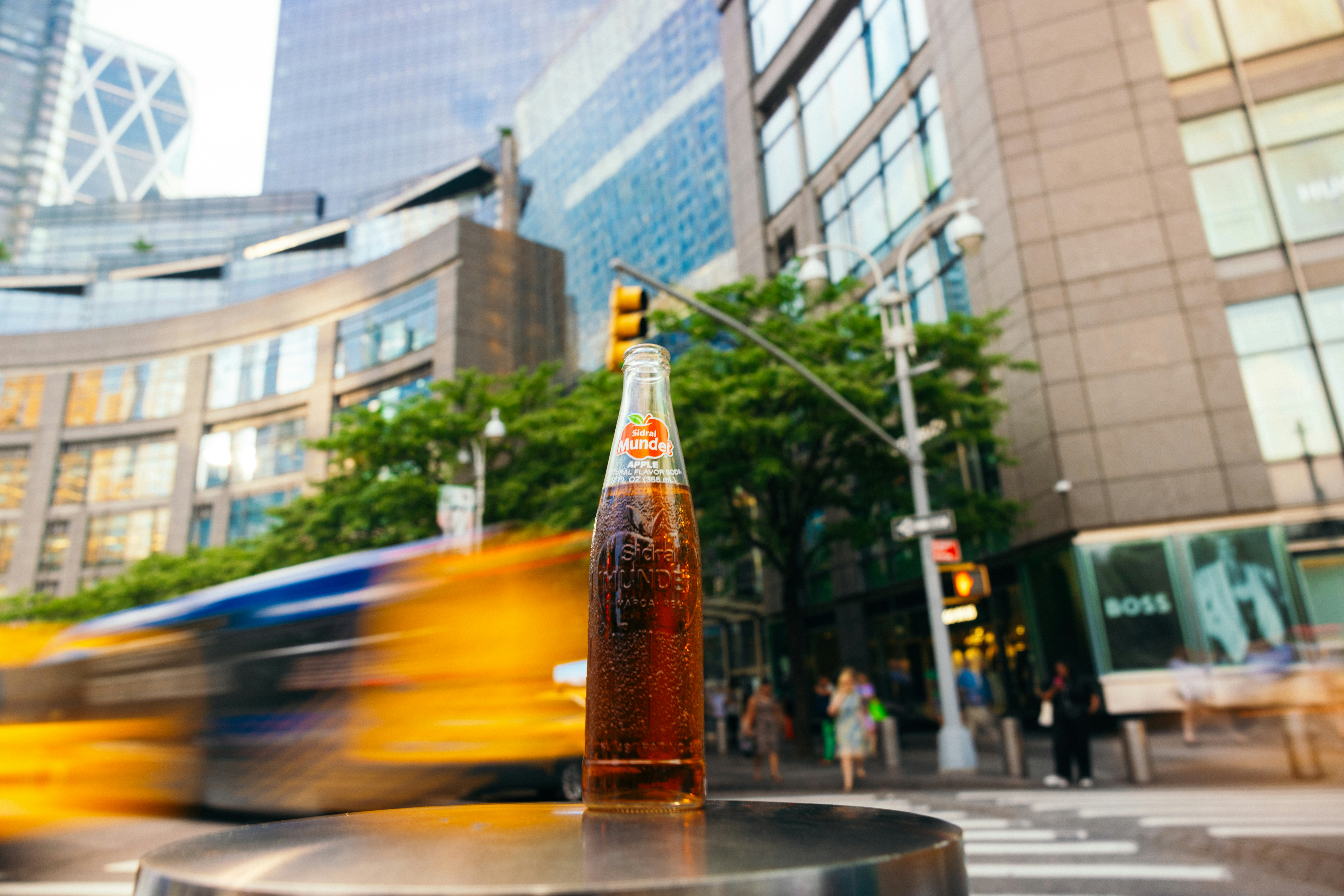 A Quiet Bottled Moment on a City Pedestal Amid Blurred Traffic