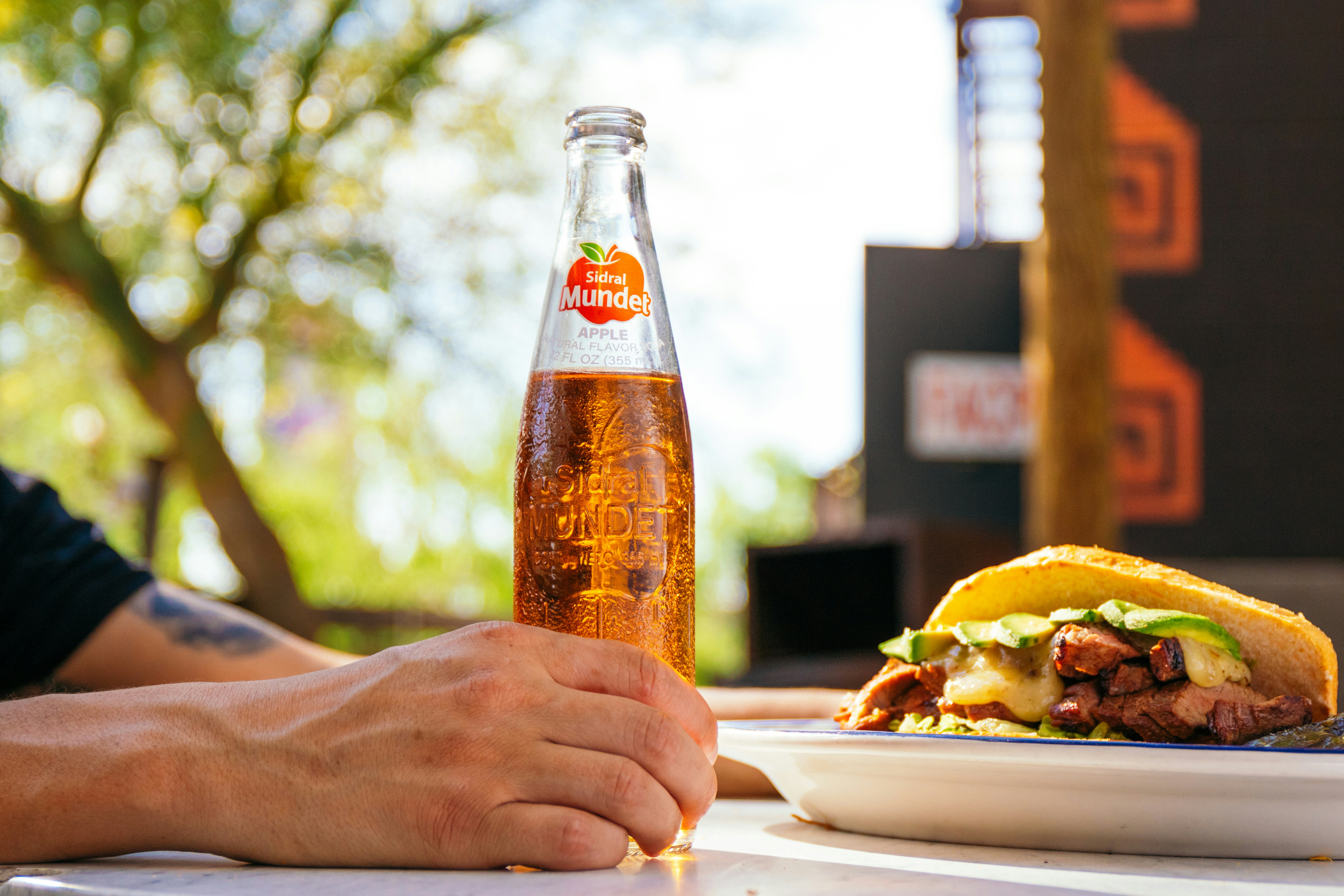 A person sitting at a table with a plate of food and a bottle of soda ...
