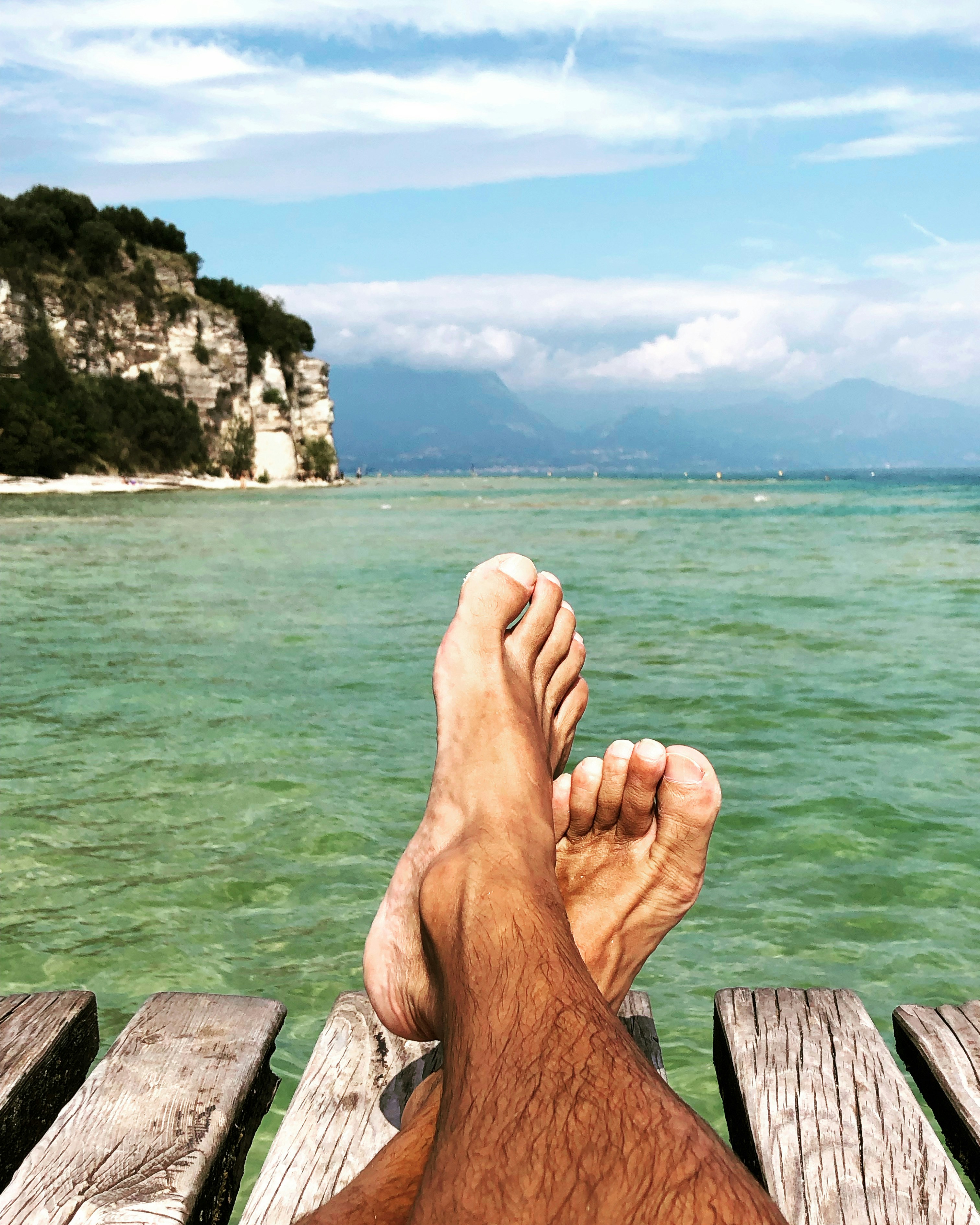 A man laying on a wooden dock next to the ocean photo – Free Beach ...
