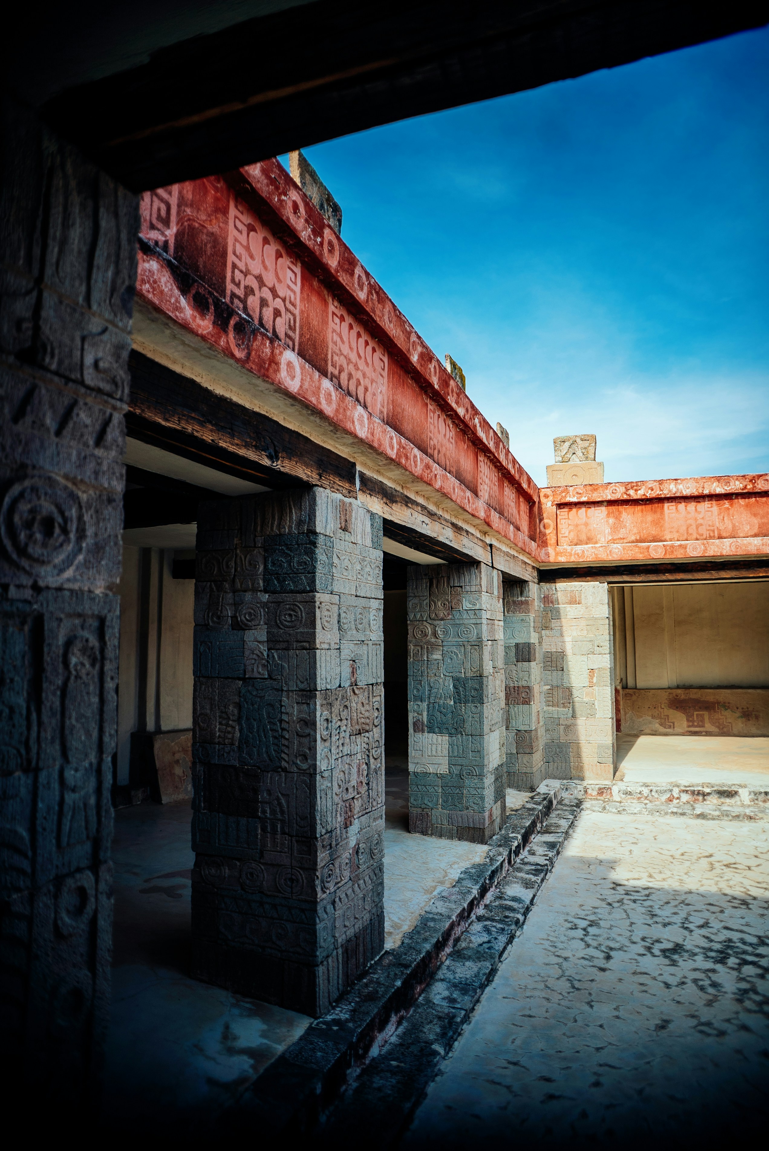 Sunlit Terrace Beneath Red Canopies and Carved Stone Columns