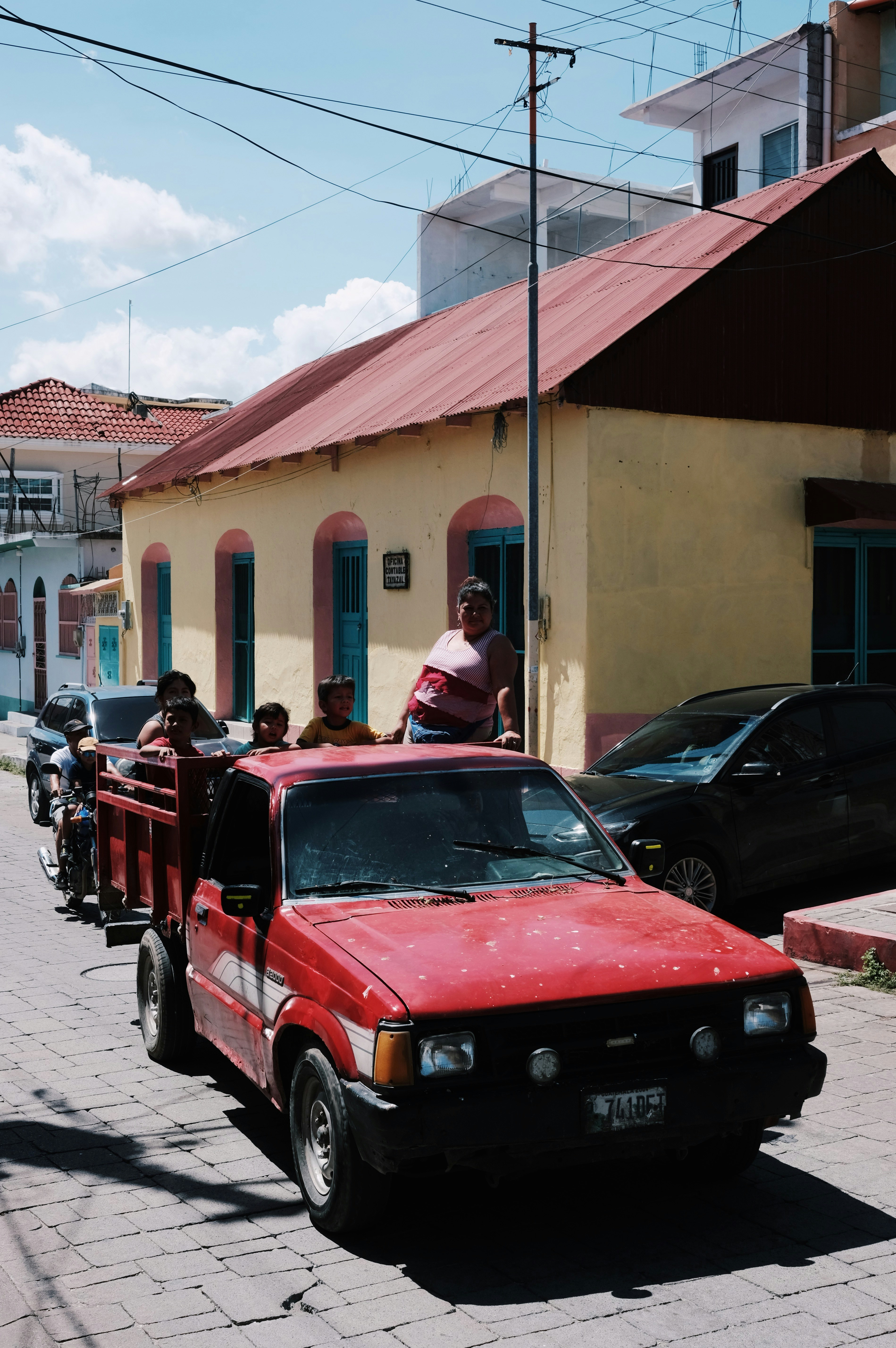 Red Pickup Rumbles Through a Colorful Caribbean Street at Noon