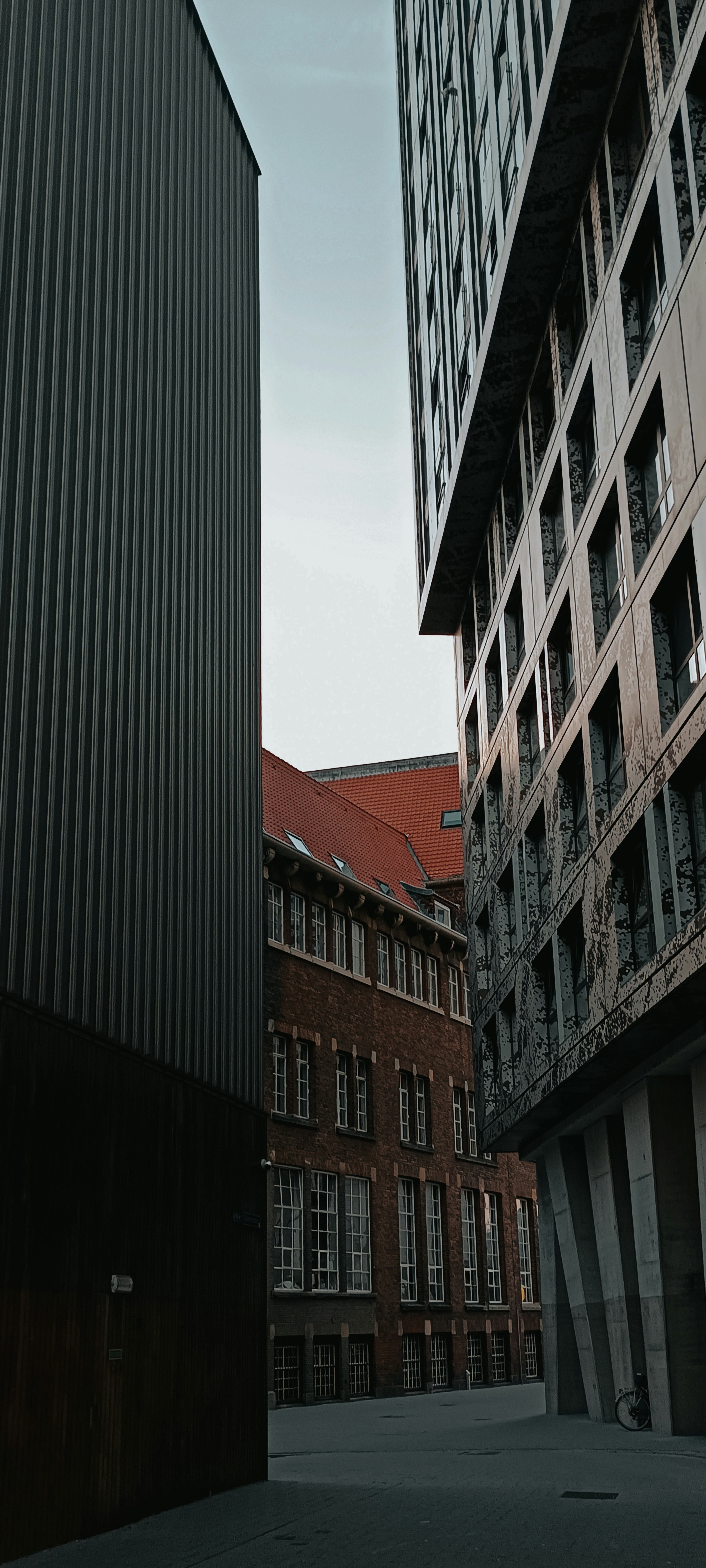 View of a narrow alley framed by contrasting modern and historical buildings, showcasing unique architectural styles.