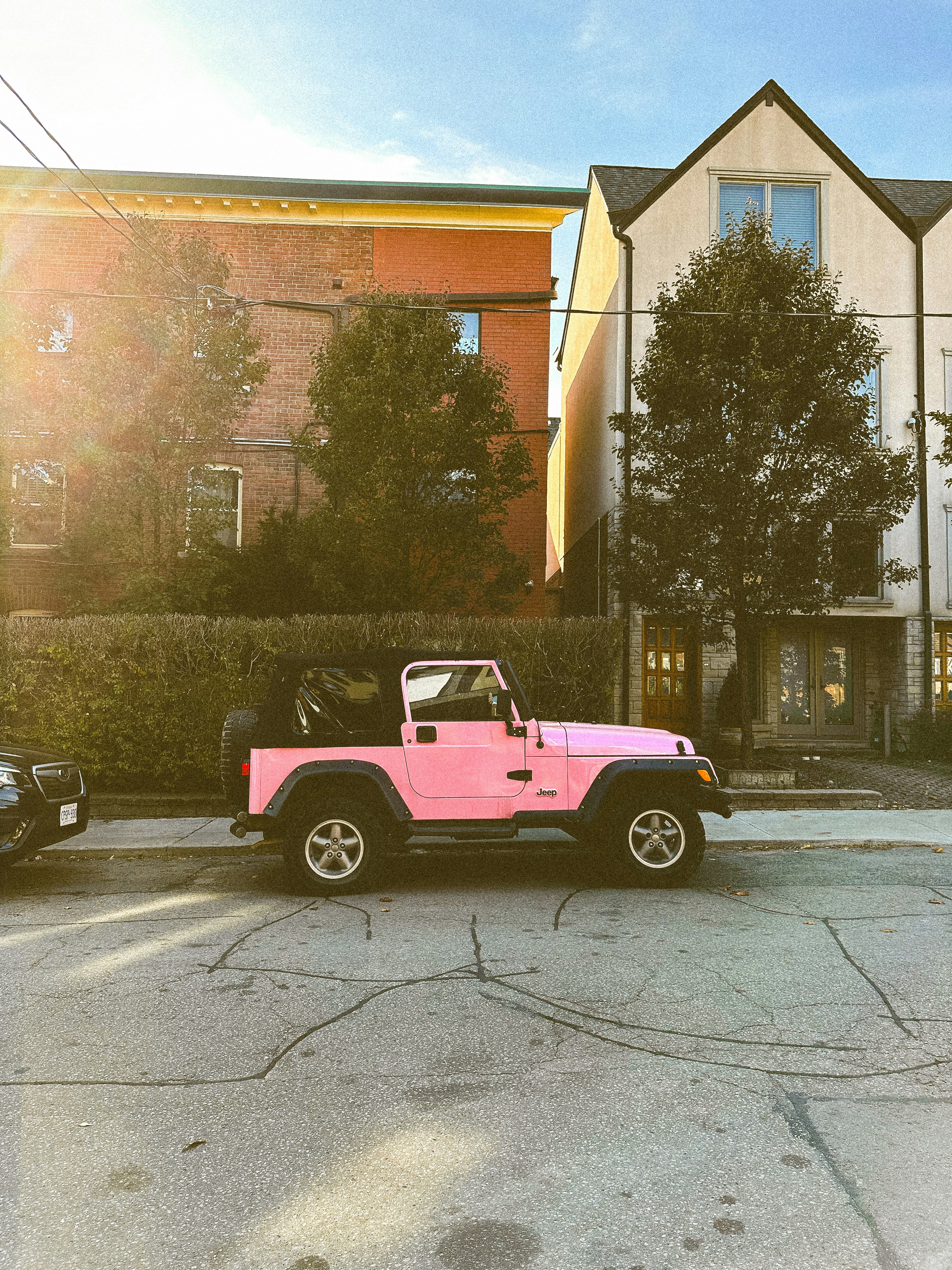 Sunlit Pink Wrangler Anchoring a Quiet City Block