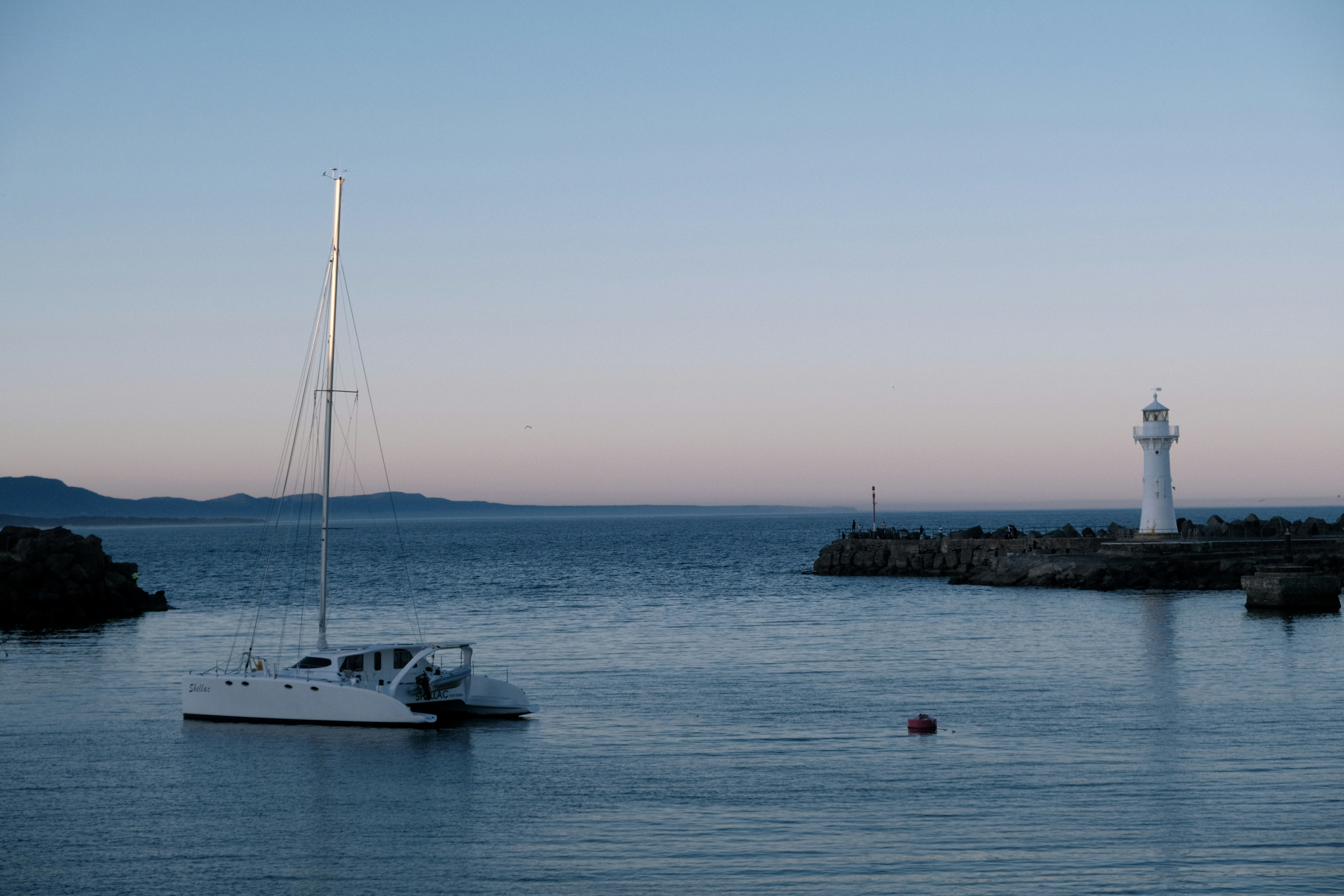 Foto zum Thema Ein Segelboot im Wasser mit einem Leuchtturm im ...