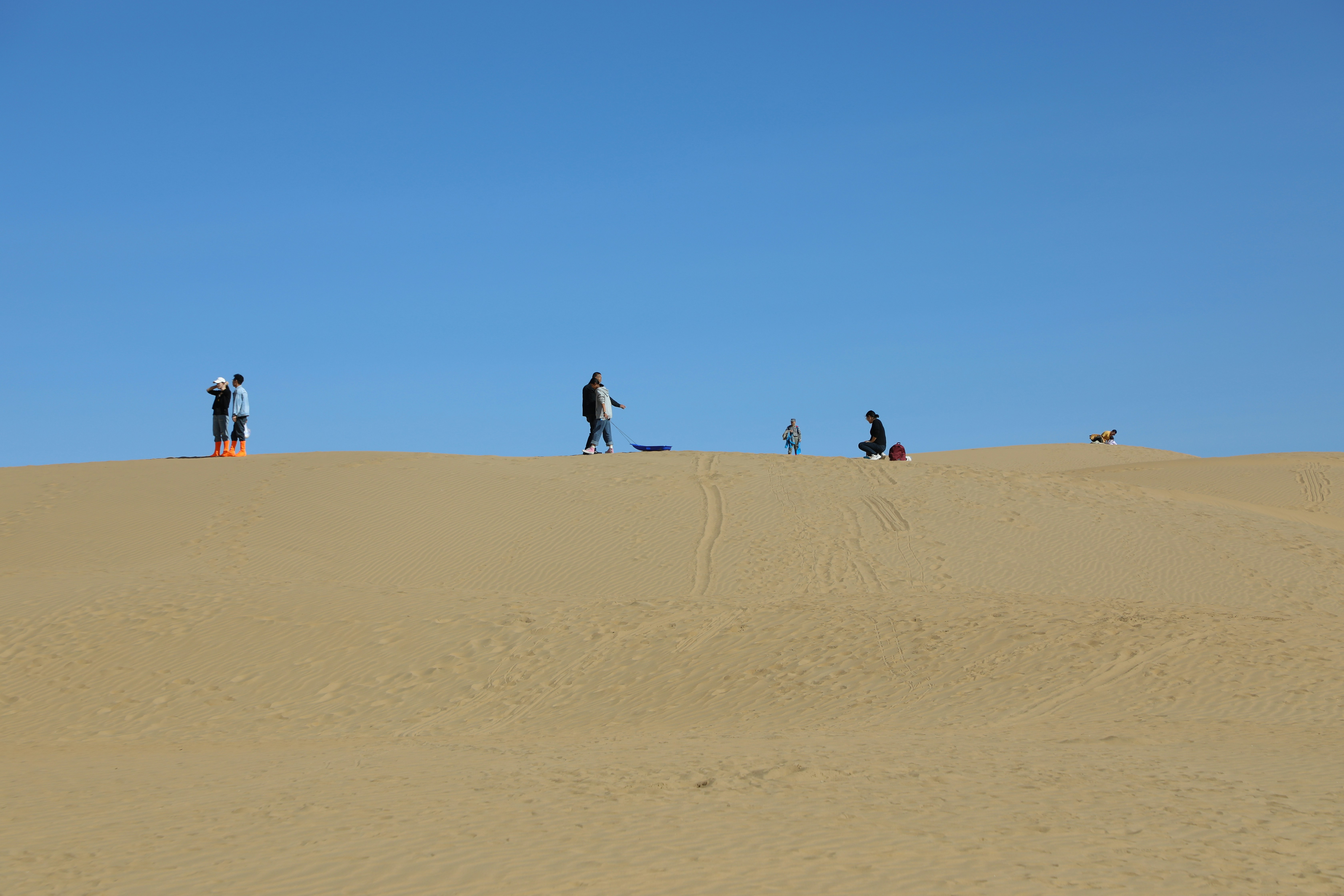 Dune Crest Trek: A Quiet Line of Explorers Against a Cerulean Sky