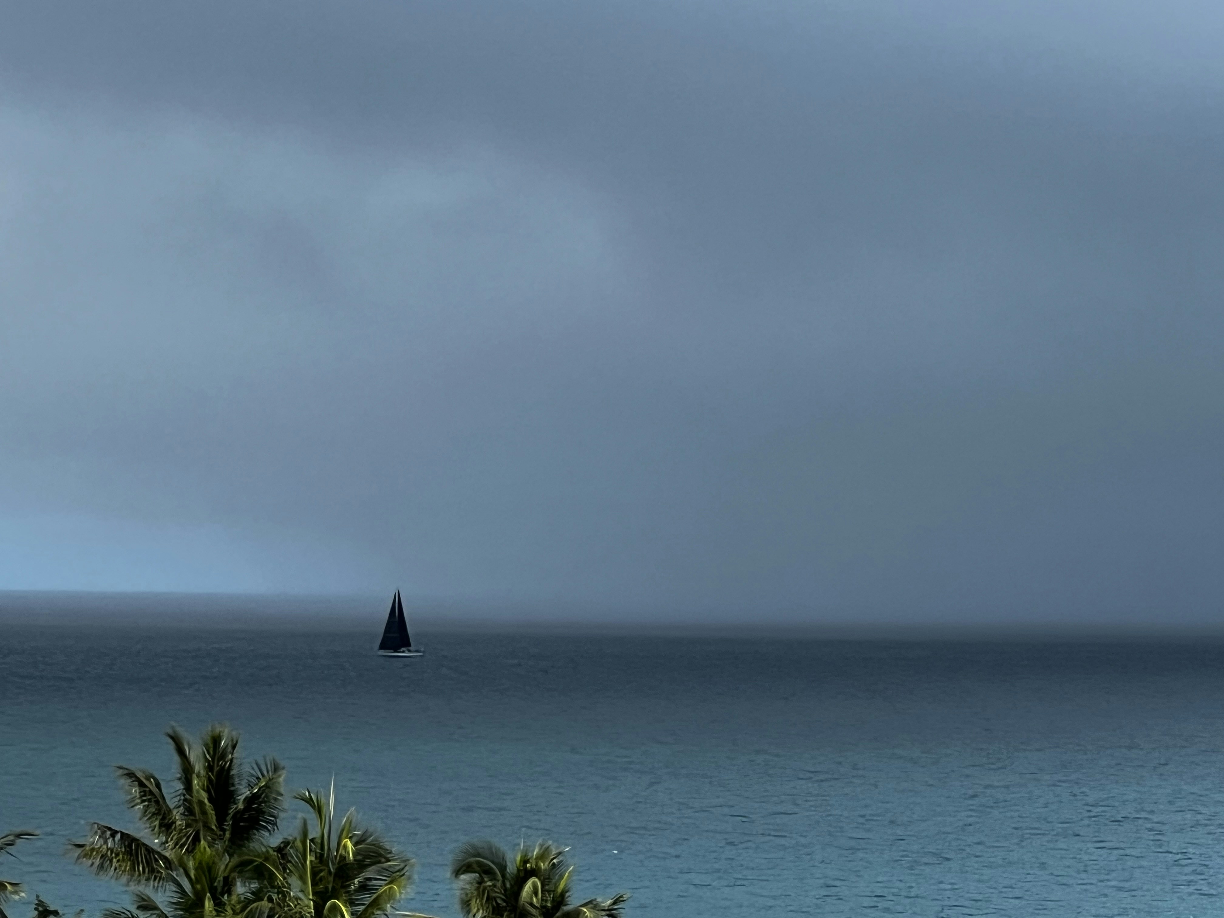 Lone Sailboat on a Moody Horizon Beneath Looming Skies