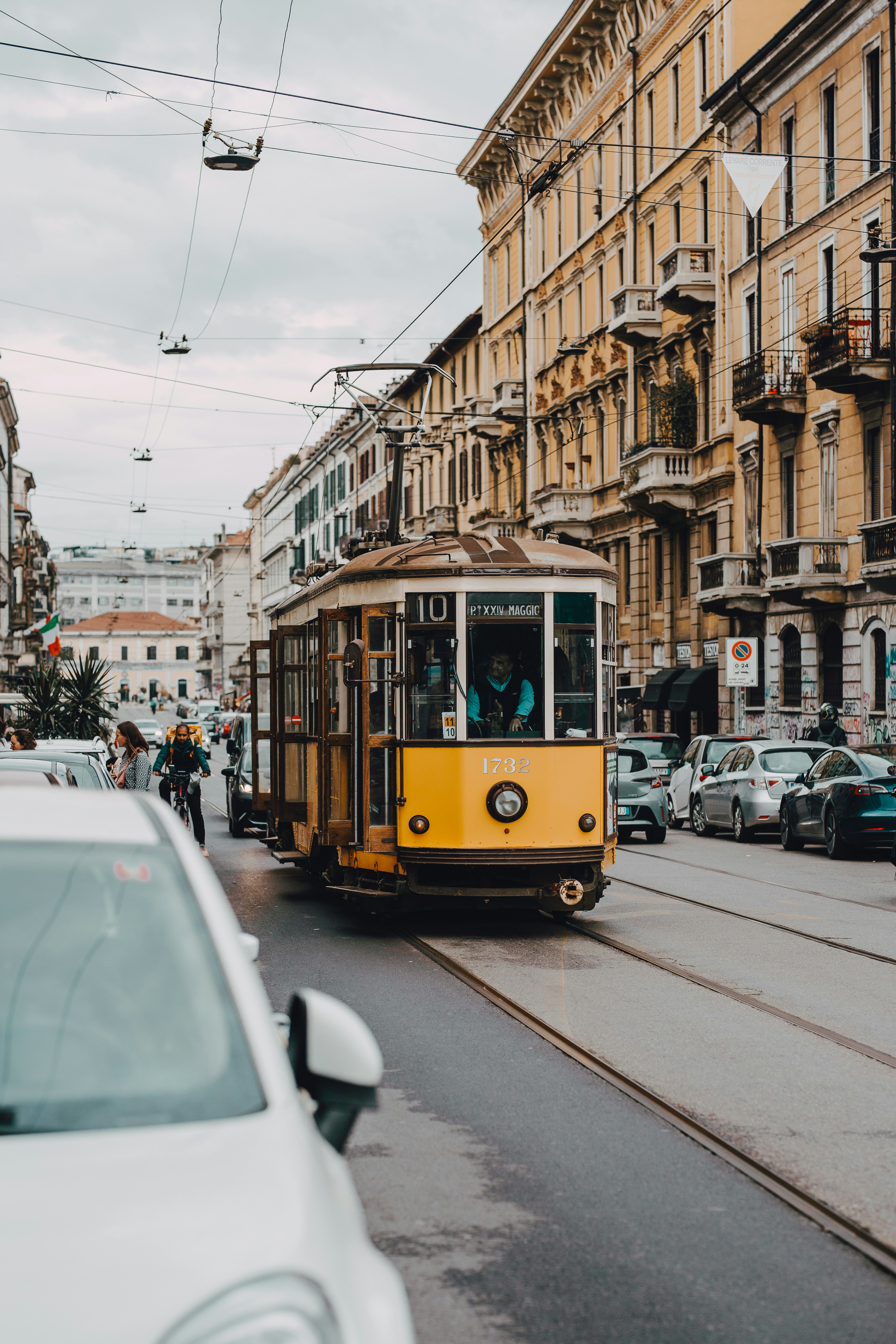 A yellow trolley driving down a street next to tall buildings photo ...