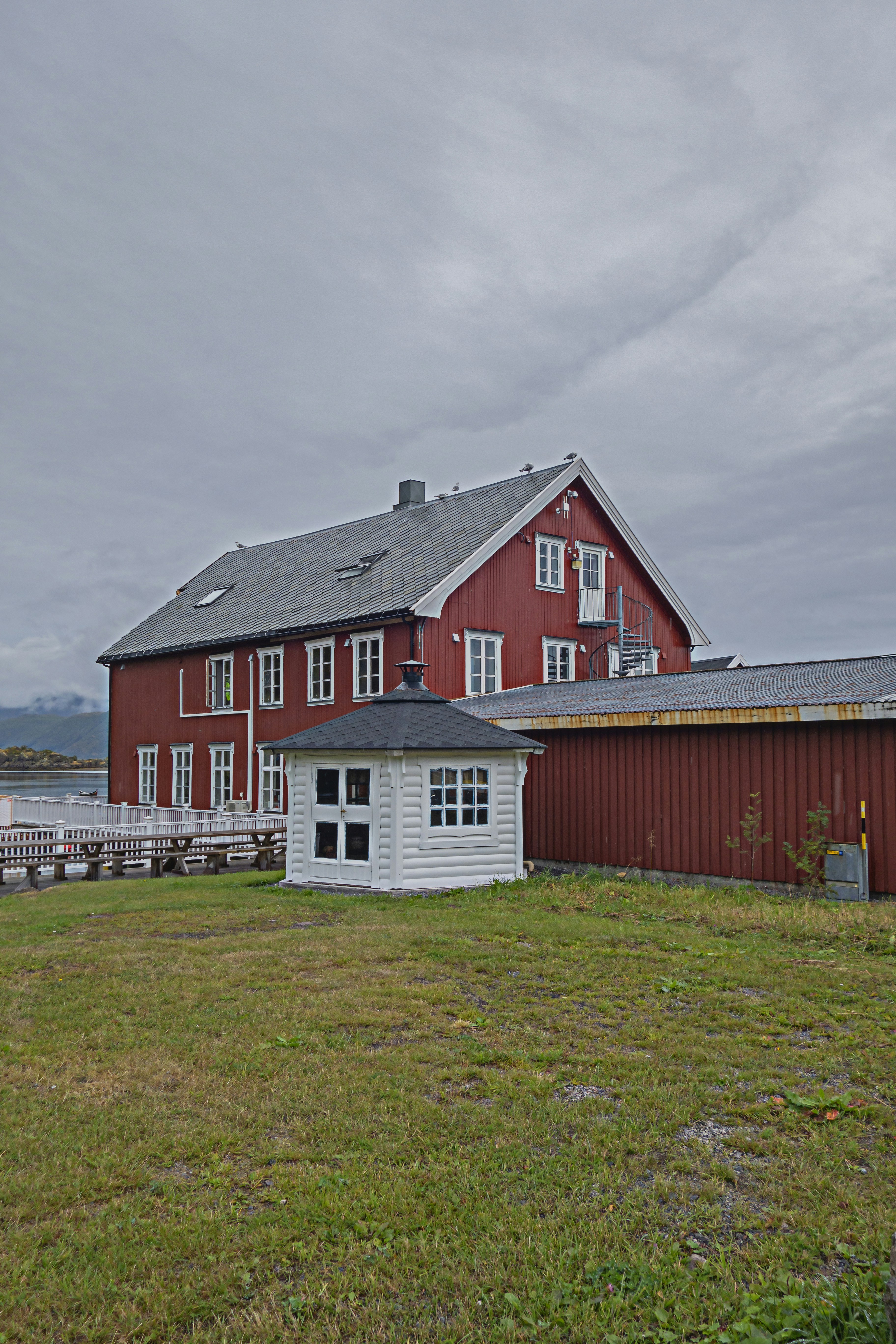 Red Coastal House and White Shed Beneath a Looming Gray Sky