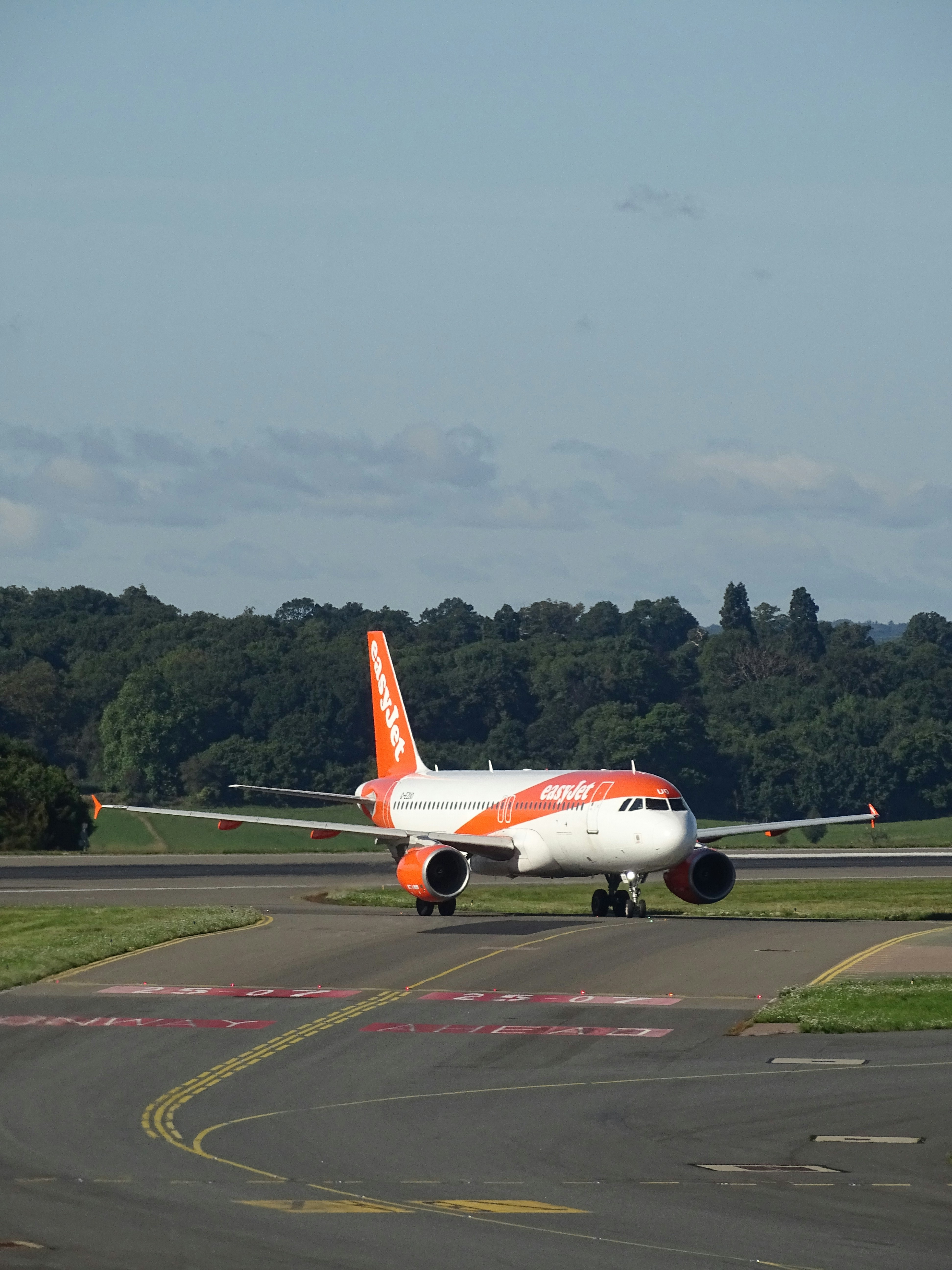 An orange and white airplane is on the runway photo – Free London luton ...