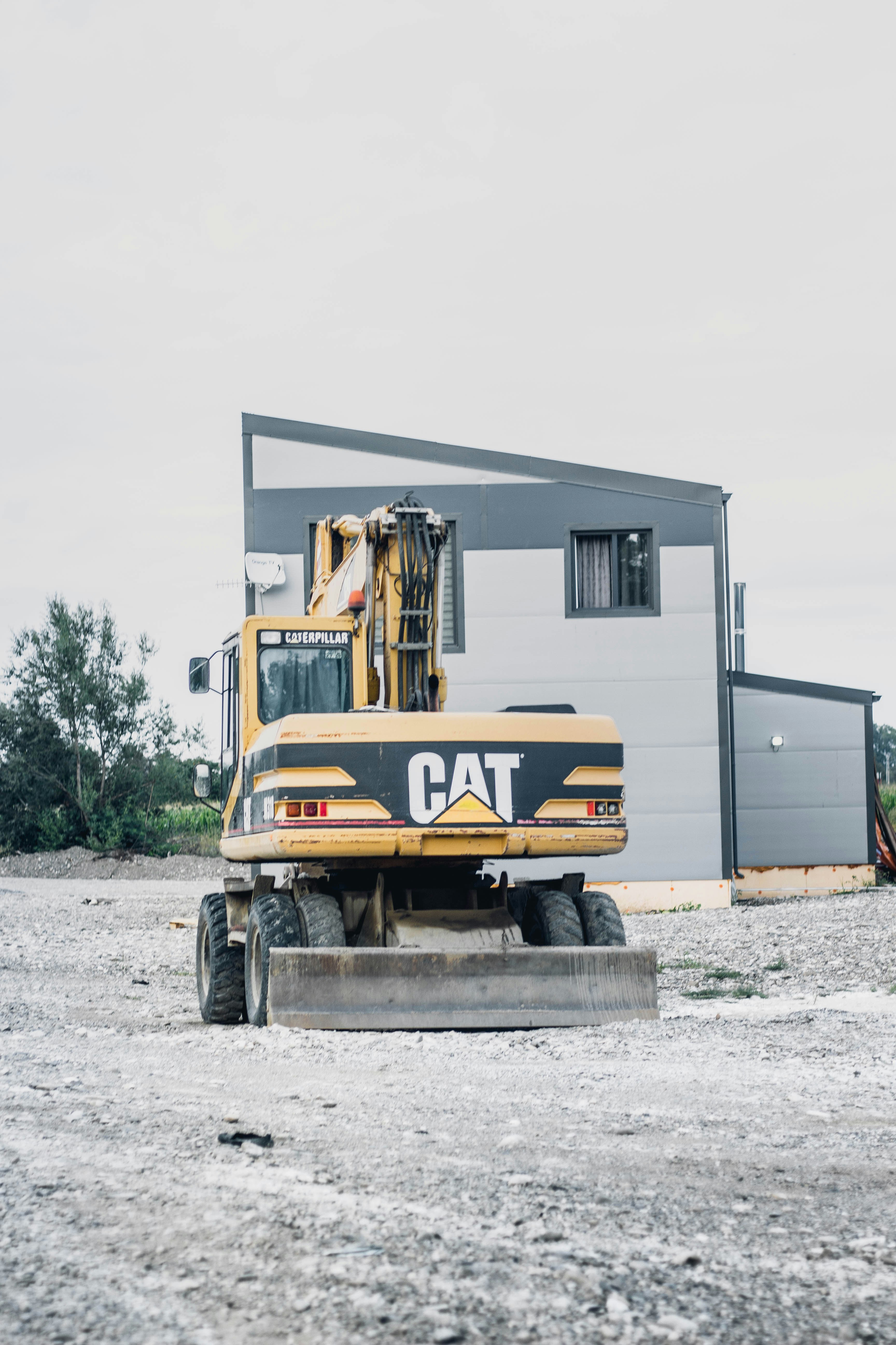 CAT Excavator at the Edge of a Modern Shell