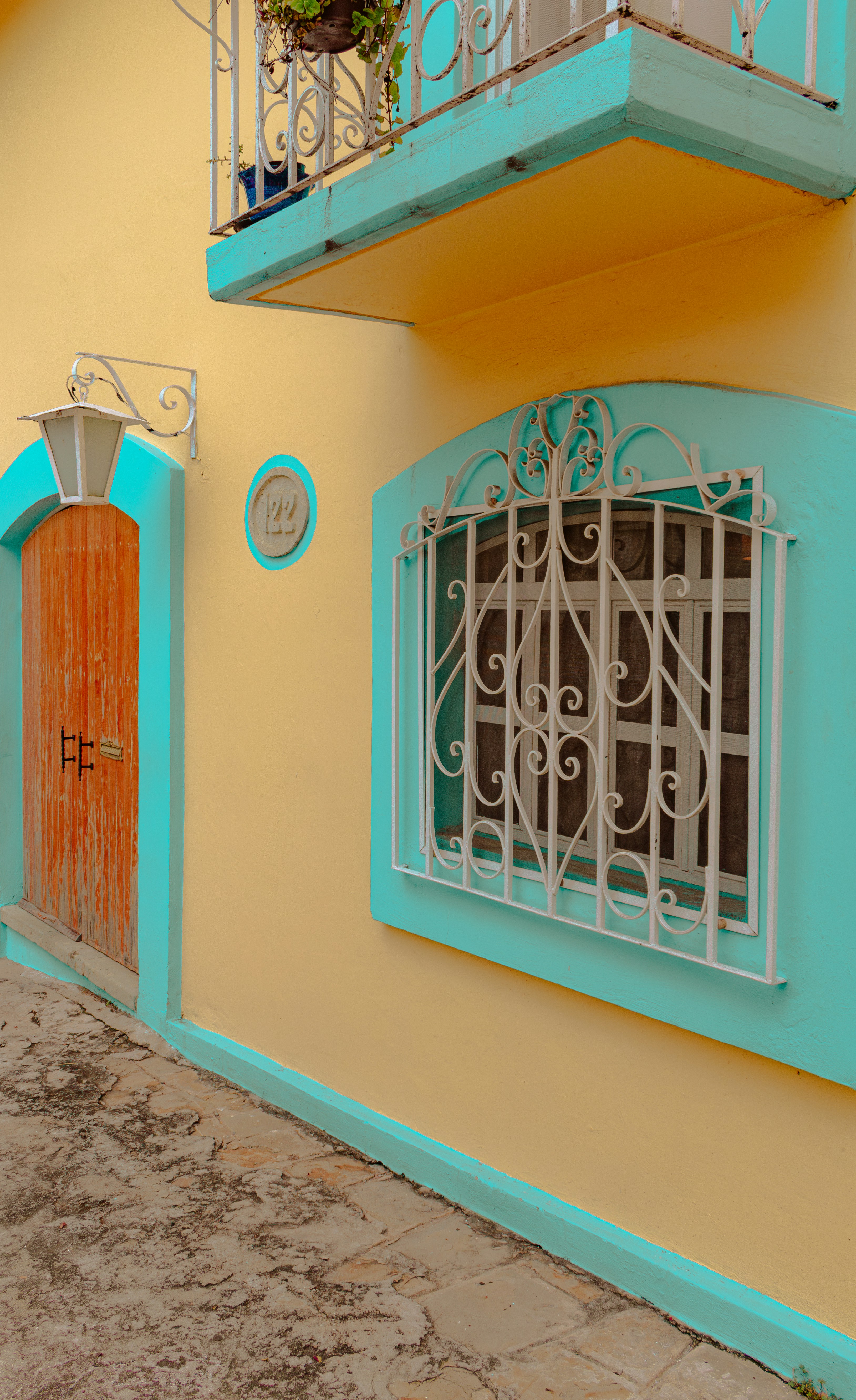Sunlit Turquoise Trim Encasing an Ember-Orange Door on a Yellow Facade