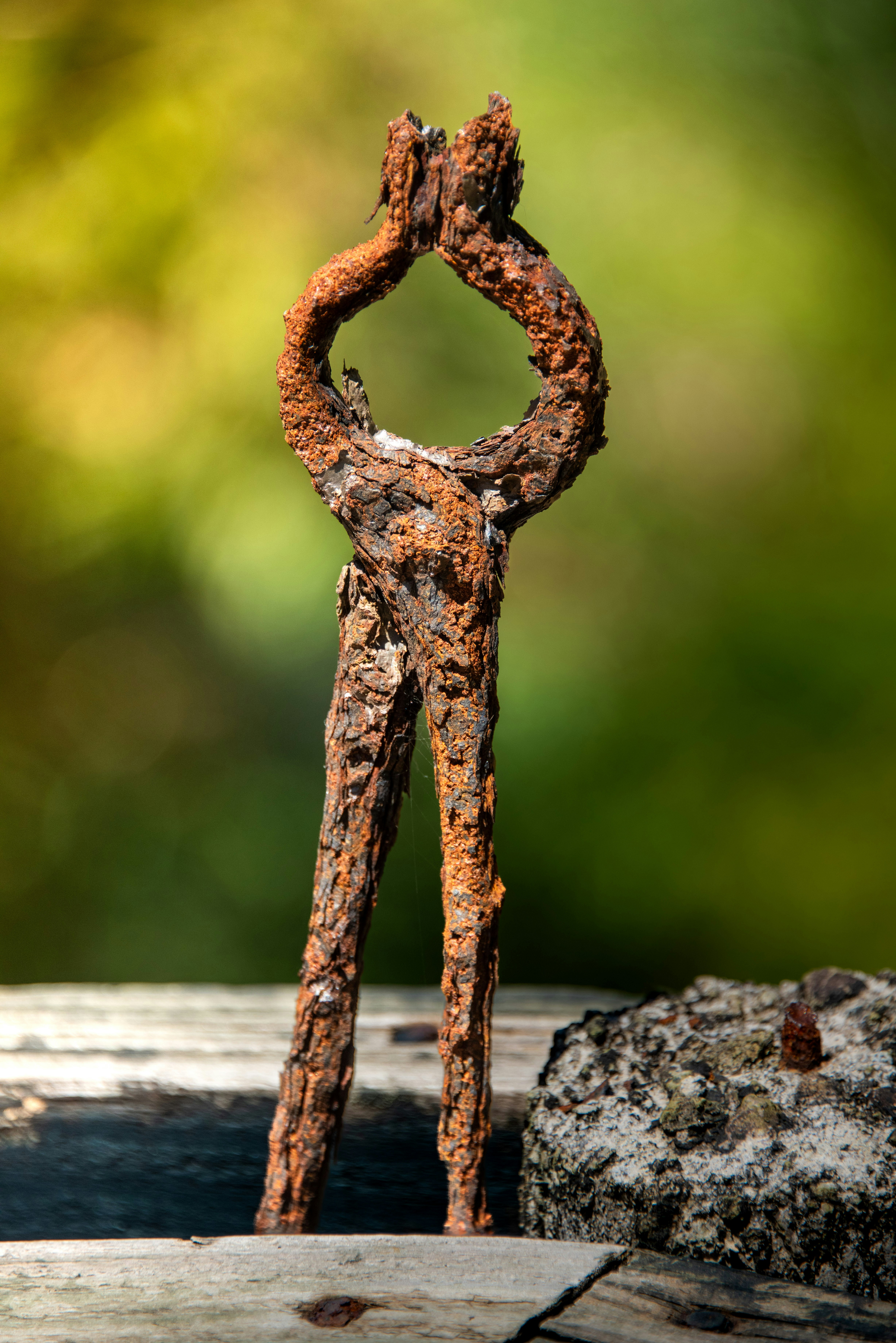 A rusted metal figure standing on a wooden surface photo – Free Wood ...