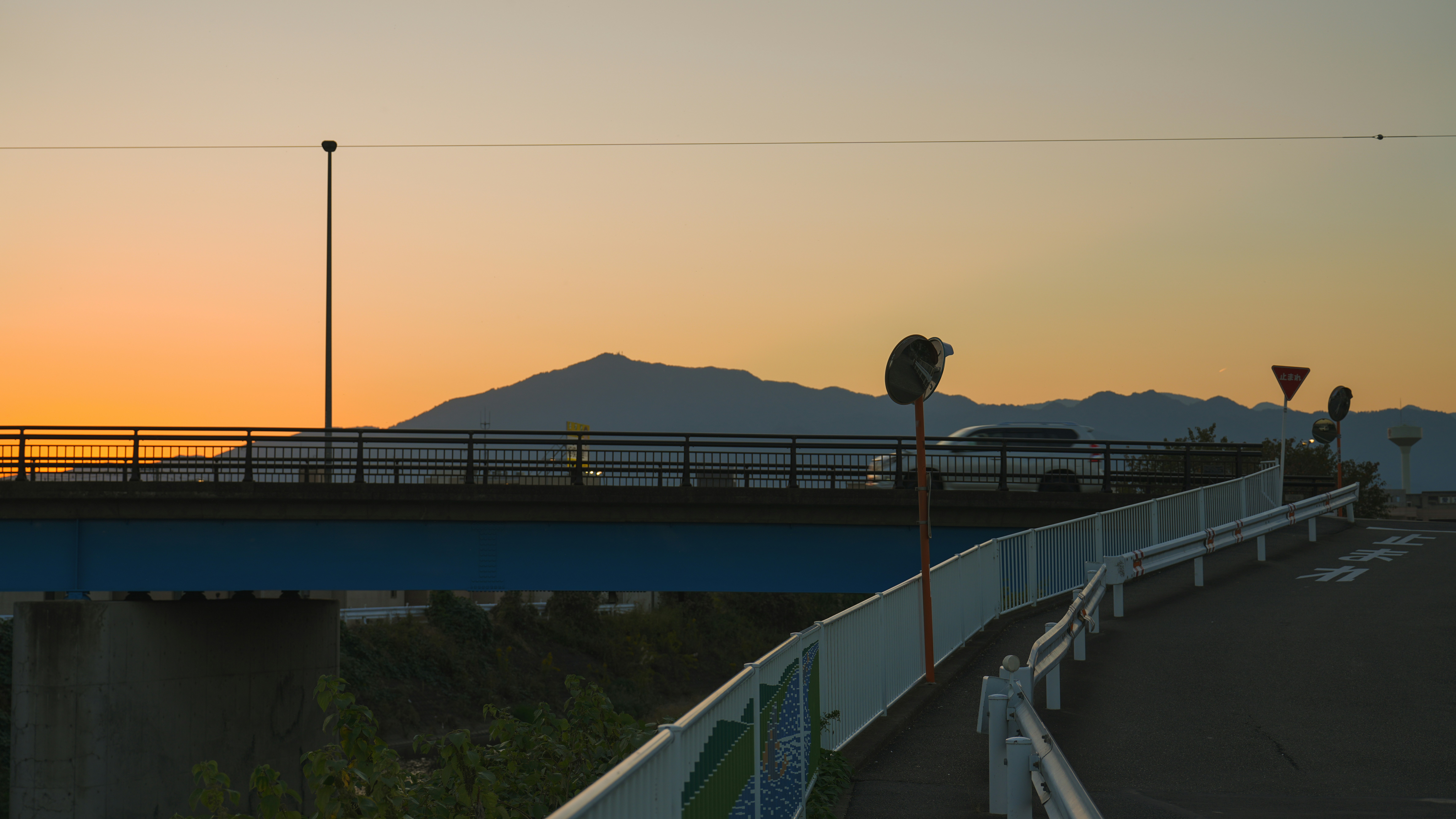 Evening Arc: Sunset Light Traces a Quiet Bridge toward the Mountain Ridge