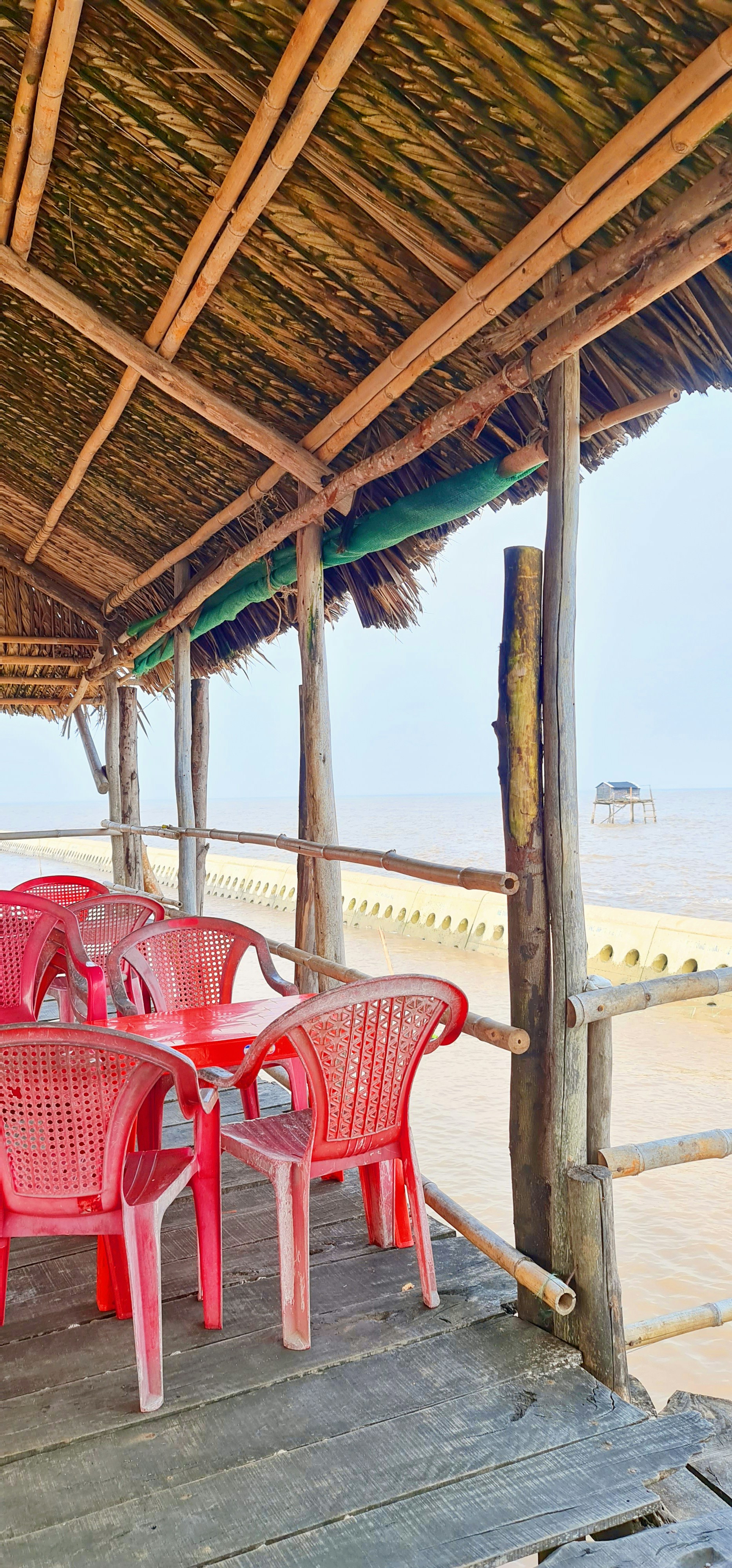 a group of red chairs sitting under a thatched roof