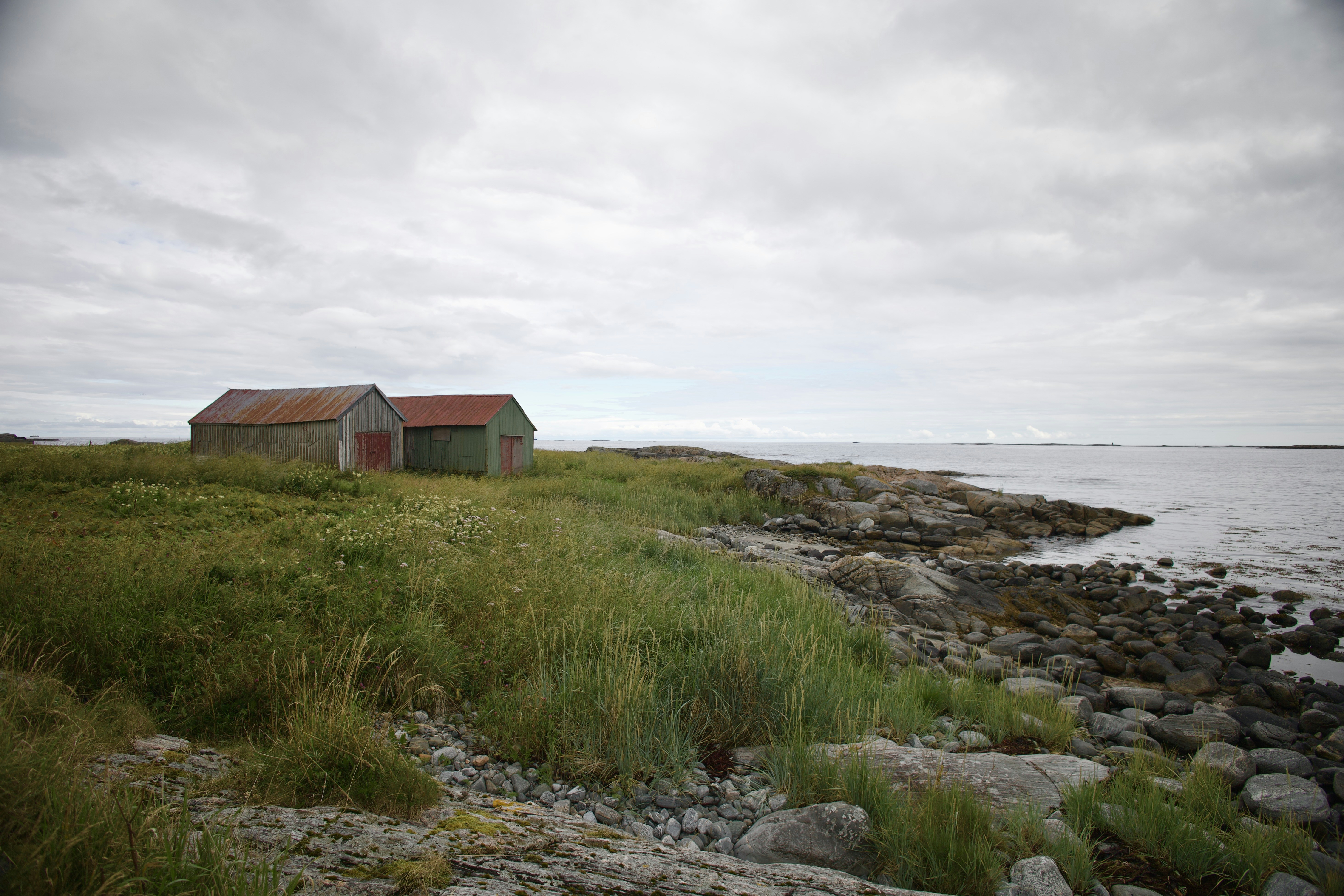 An old shack sitting on the shore of a body of water photo – Free ...