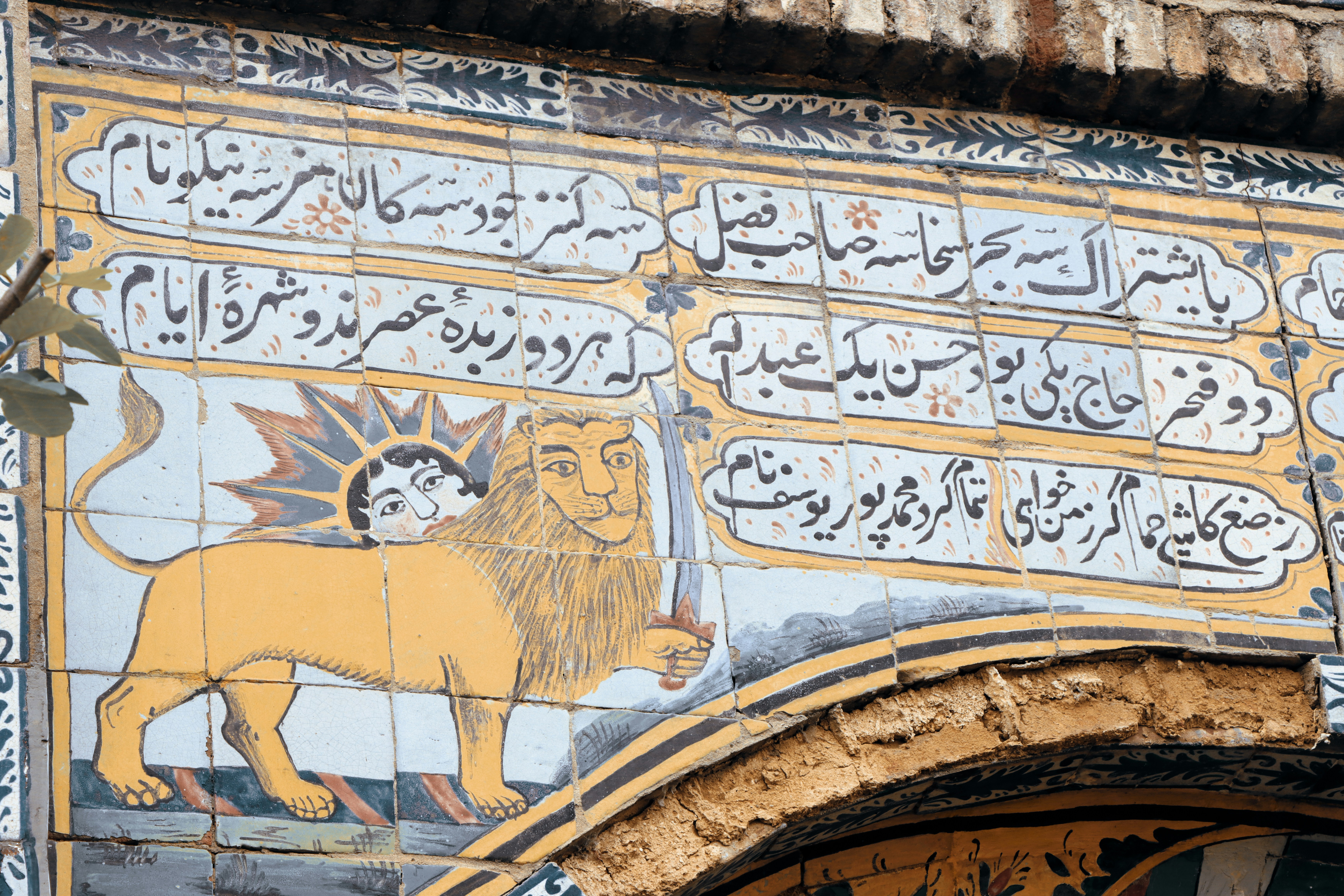 Sun-Lit Lion Over Script: A Ceramic Tile Tale from a Weathered Arch