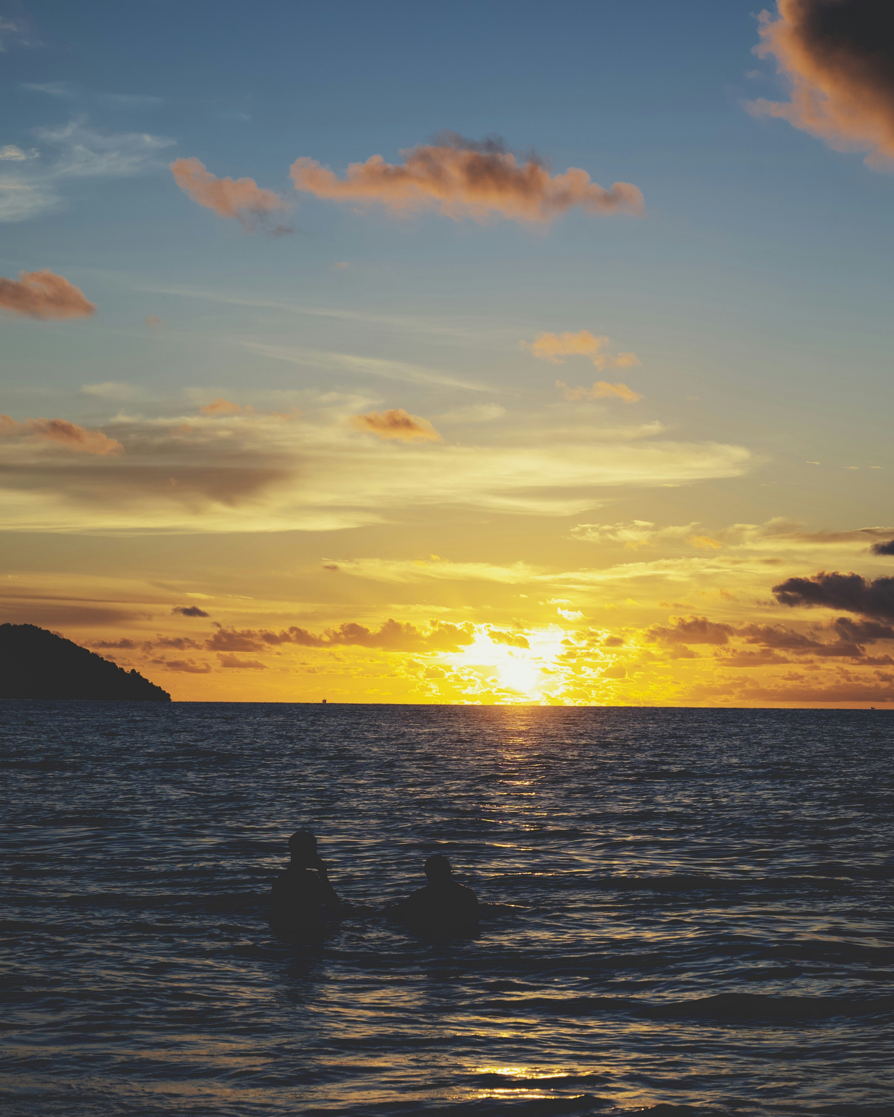 Horizon of Quiet Fire: Silhouettes at Sunset Over Calm Seas
