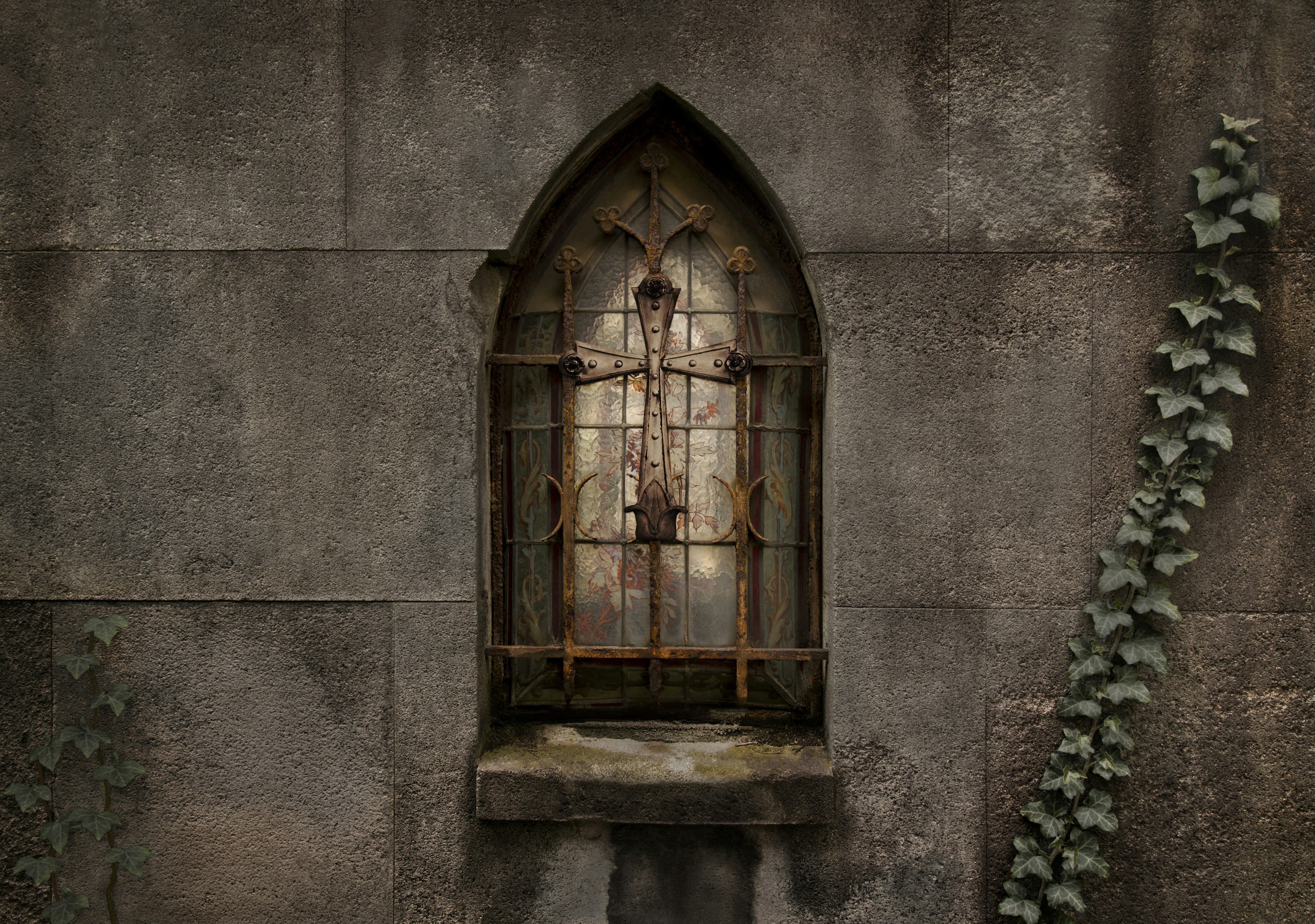Ivy-Graced Arch: A Rusted Window Framed by Weathered Stone