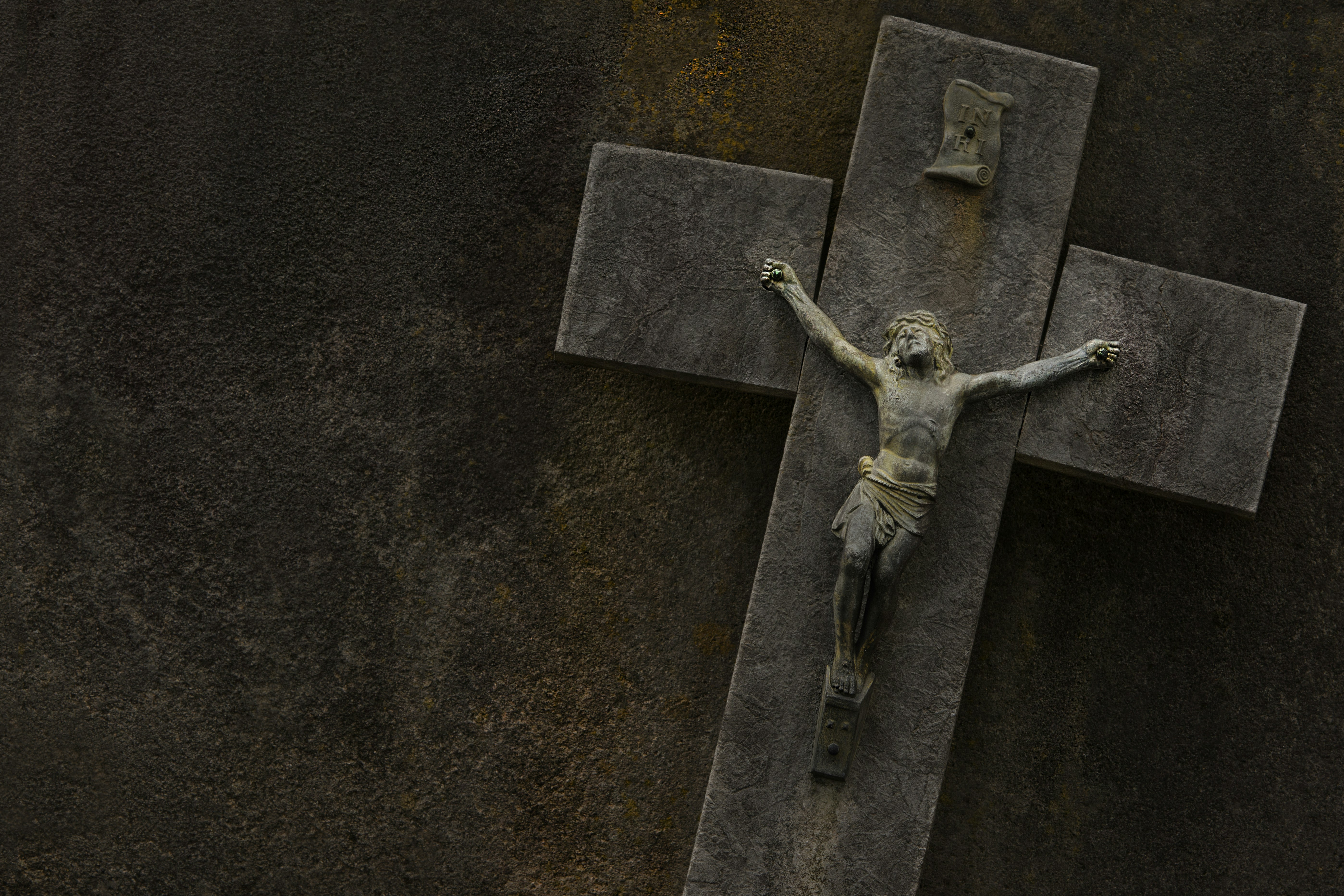 Weathered crucifix mounted on a textured wall, embodying themes of faith and endurance.