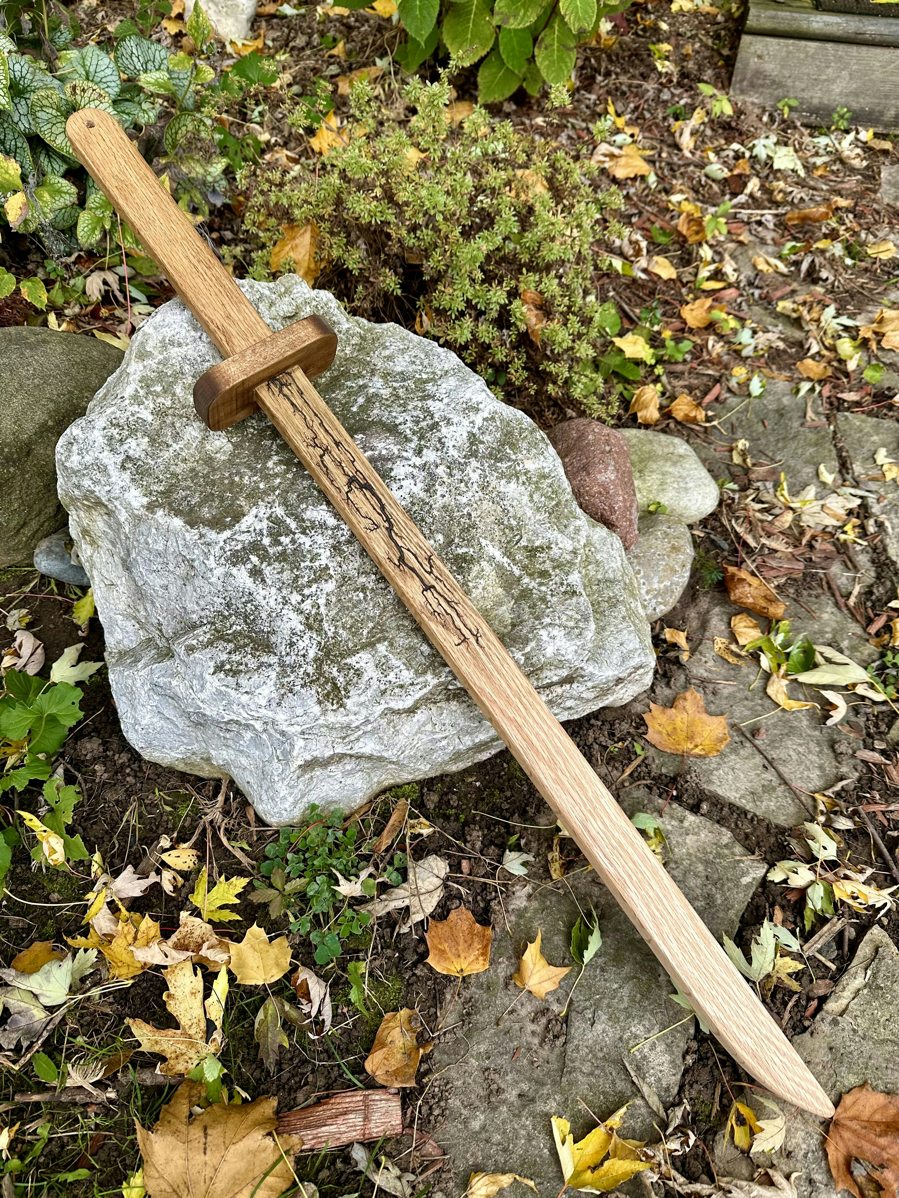 A wooden sword laying on top of a rock photo – Free Wi Image on Unsplash