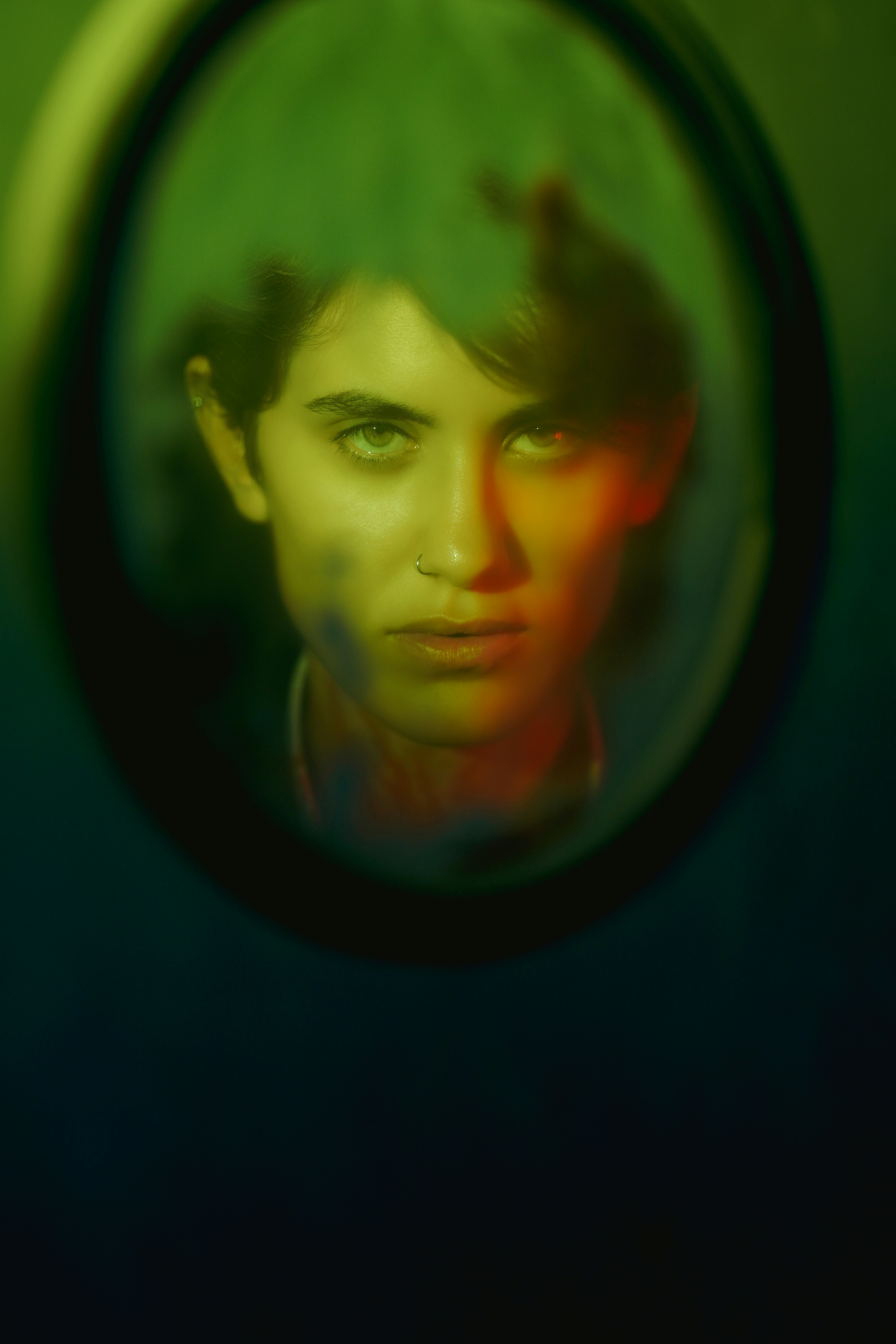 Gaze Framed by a Neon Ring: Portrait in a Color-Bathed Window