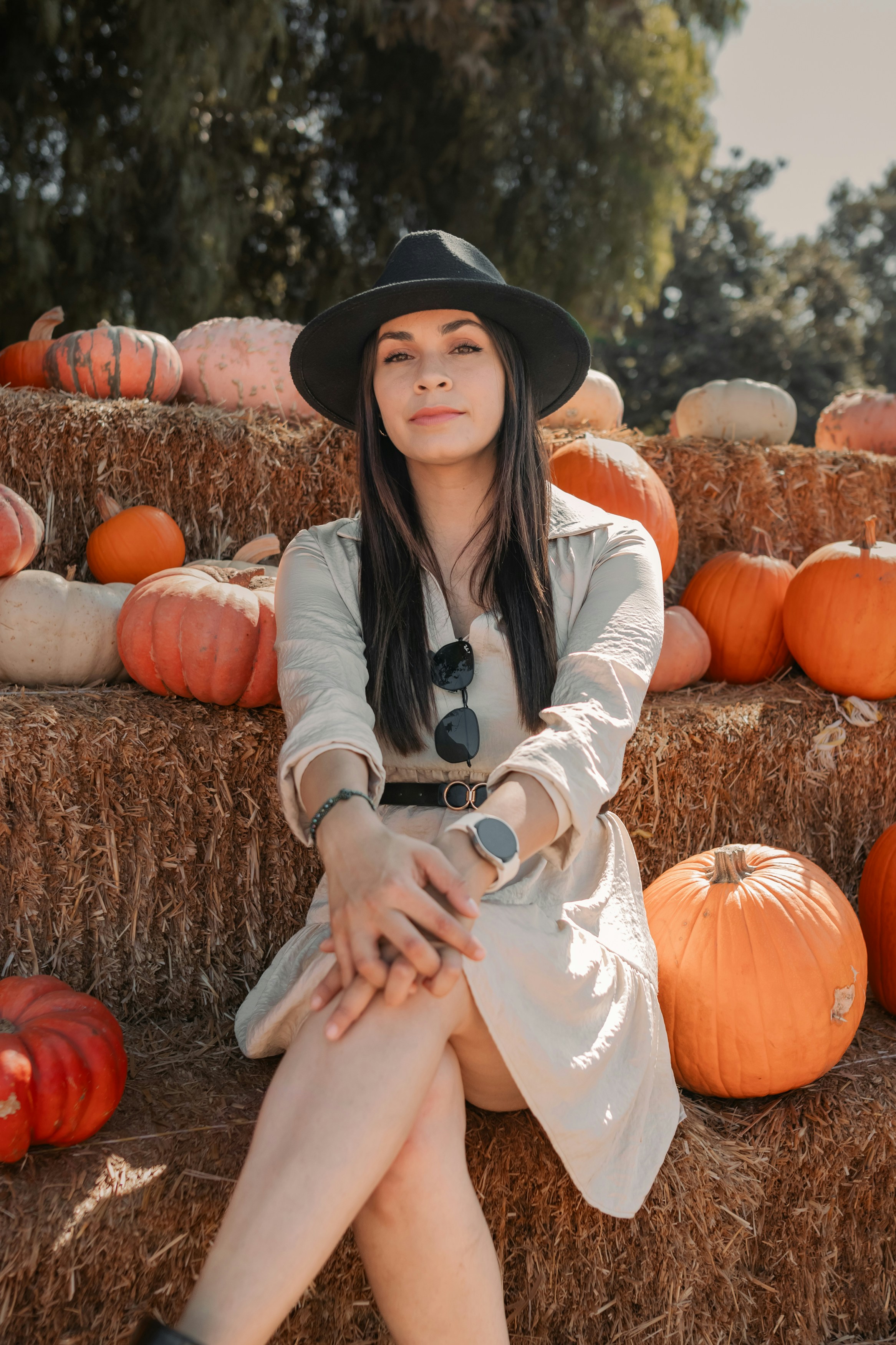 A woman sitting on hay bales with pumpkins in the background photo ...