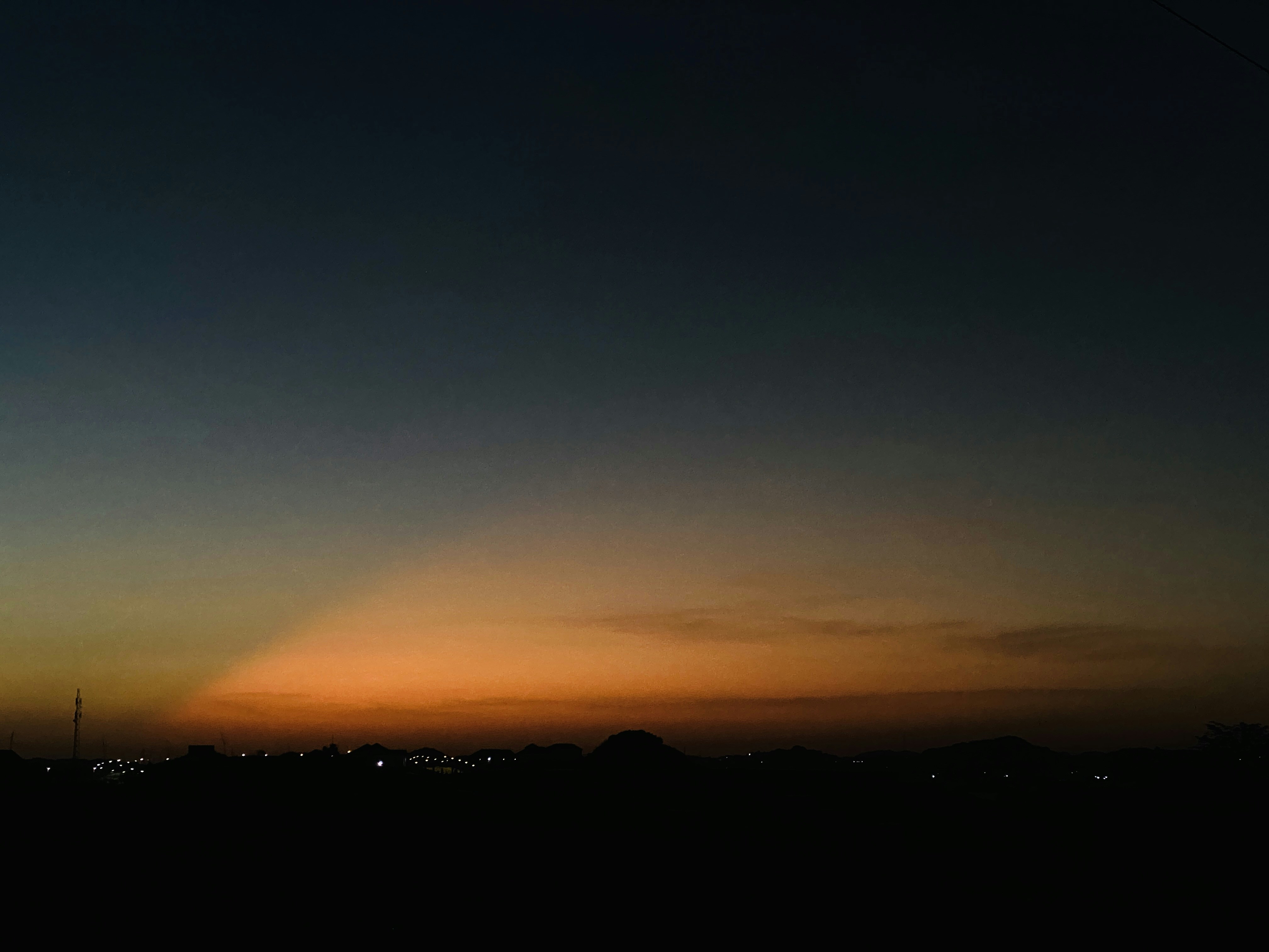 Vibrant orange and dark blue hues blend in the sky above a cityscape at dusk.