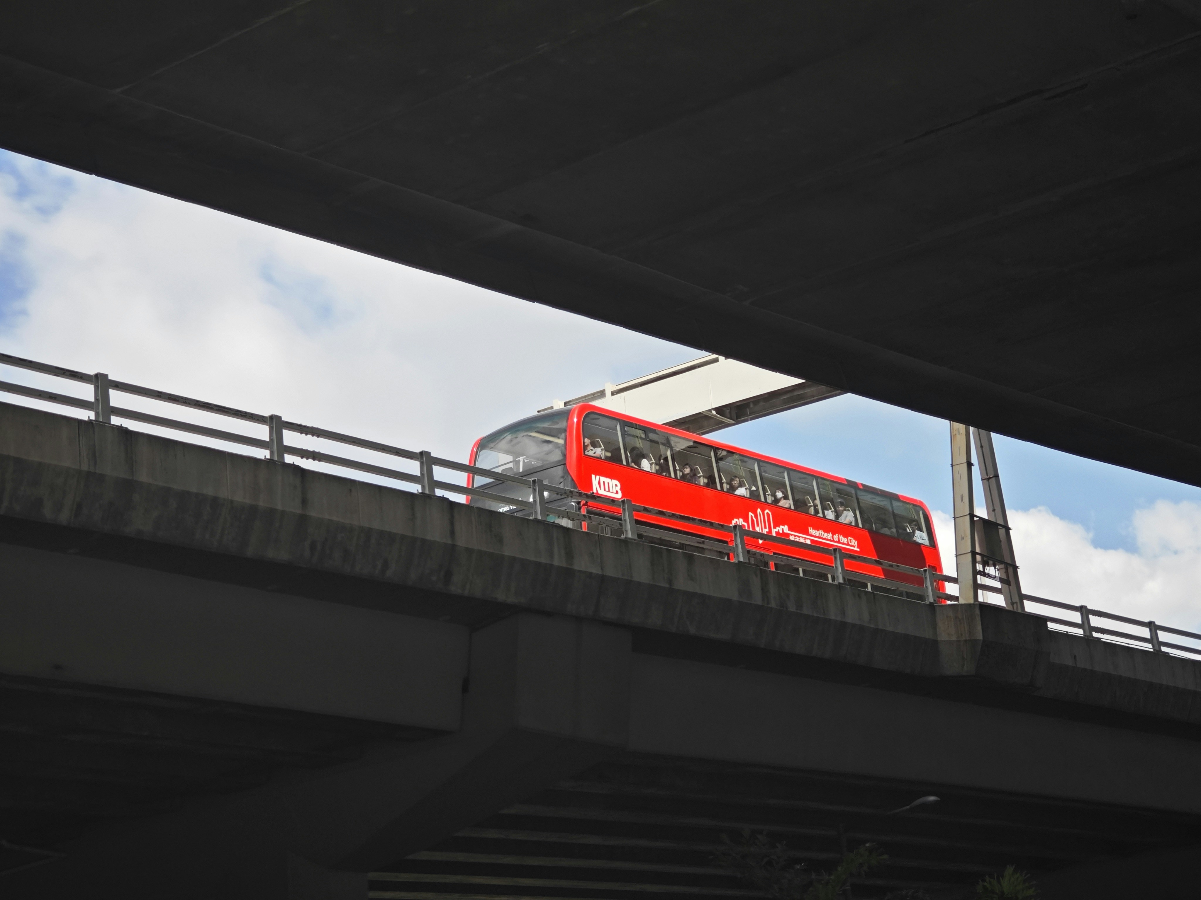 Crimson Bus at the Edge: A Red Transit on a Concrete Overpass