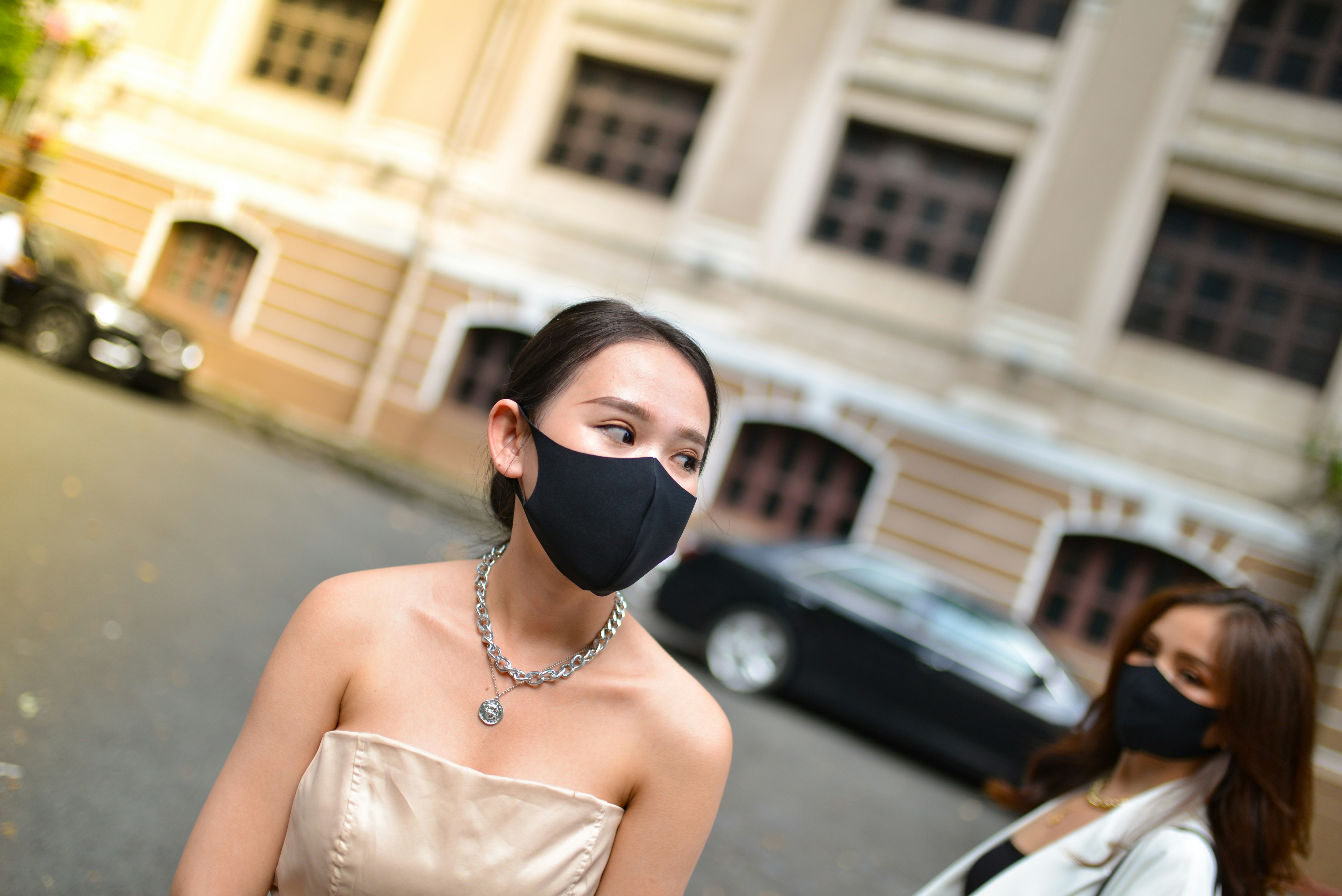 Masked Elegance on a Sunlit Street with Pastel Facades