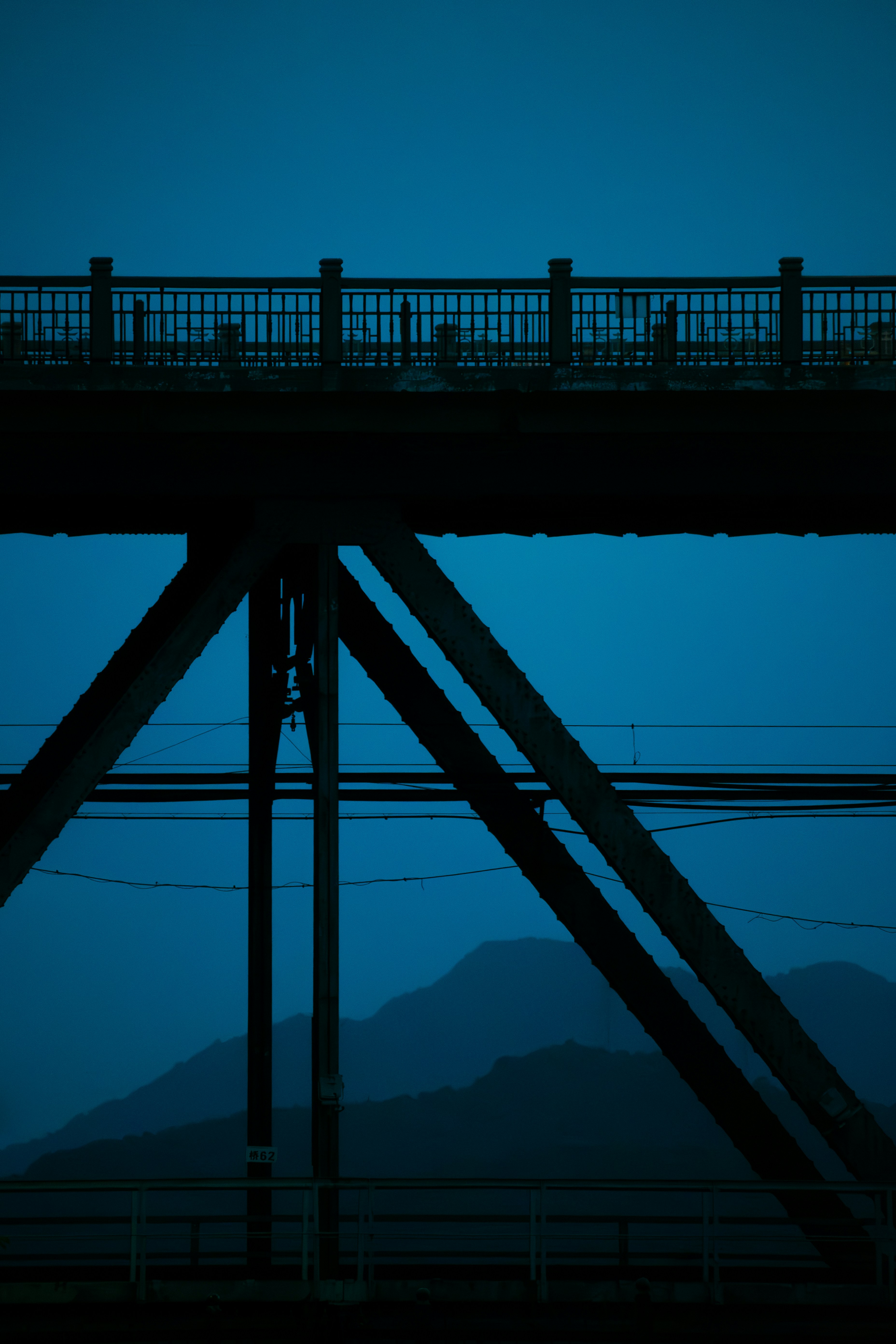 Crisscrossed Blue Hour: A Silhouetted Bridge Against a Mountain Backdrop
