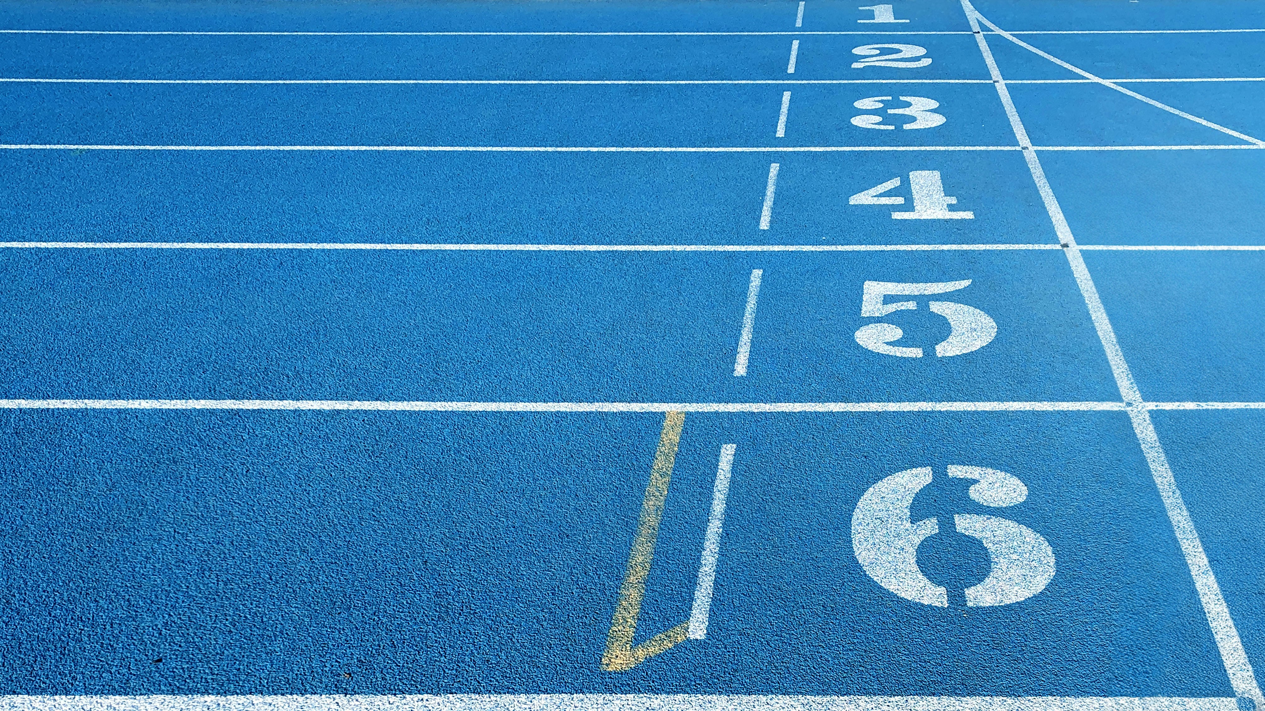 A blue running track with white numbers on it photo – Free Lane Image ...